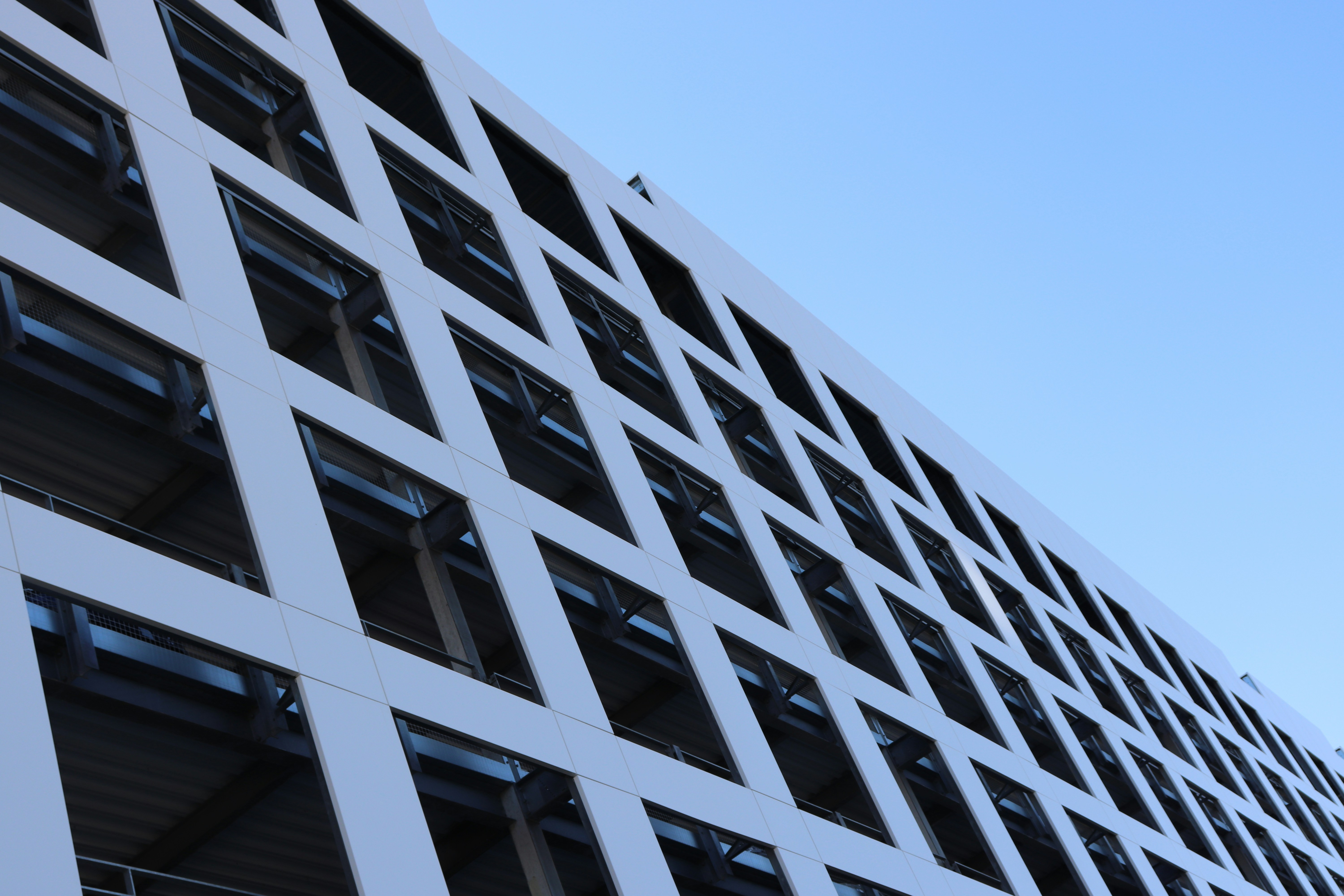 Modern building facade with repeating square windows under a clear blue sky.