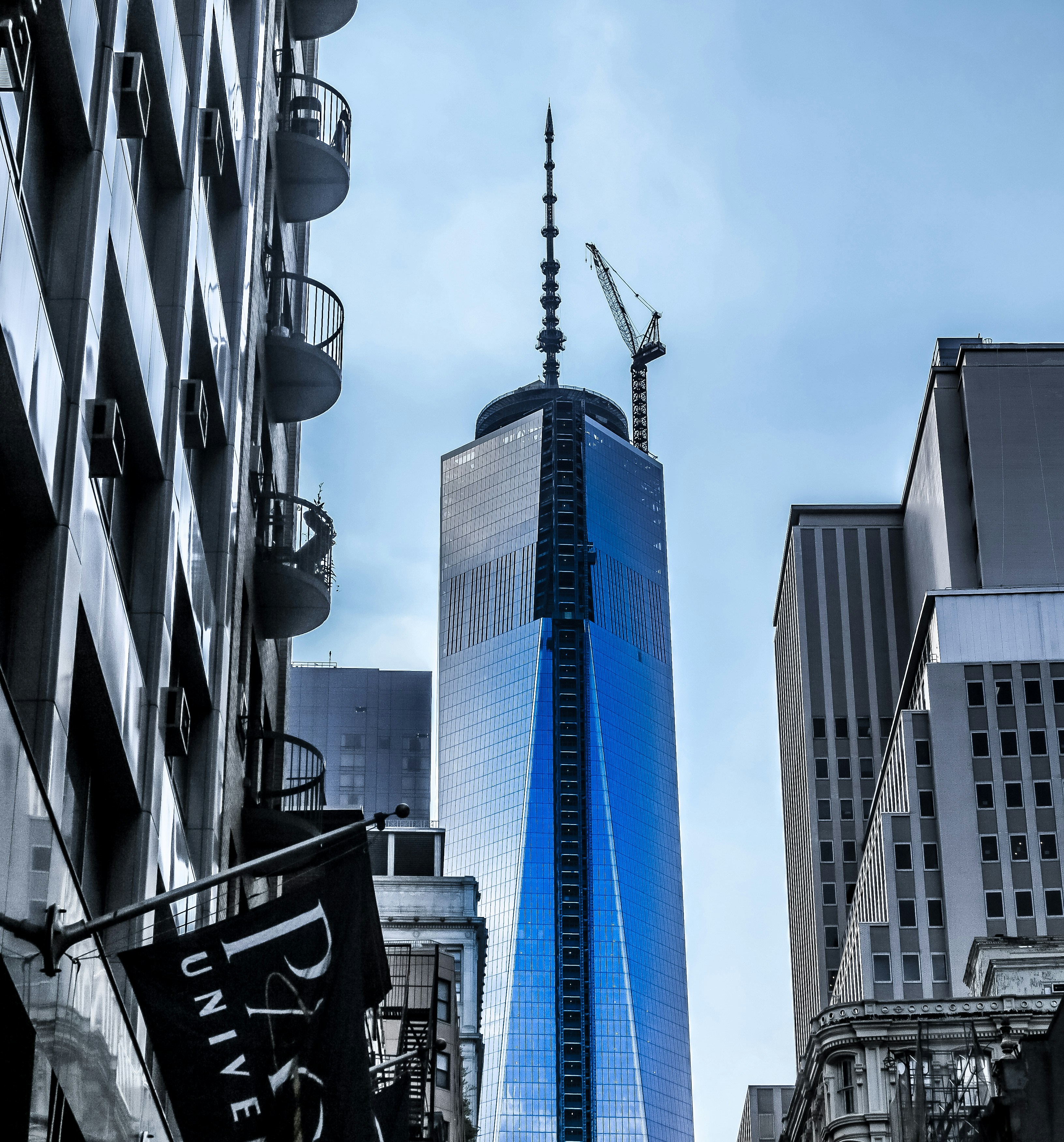 Blue Glass Spire Rises Above a Narrow City Canyon