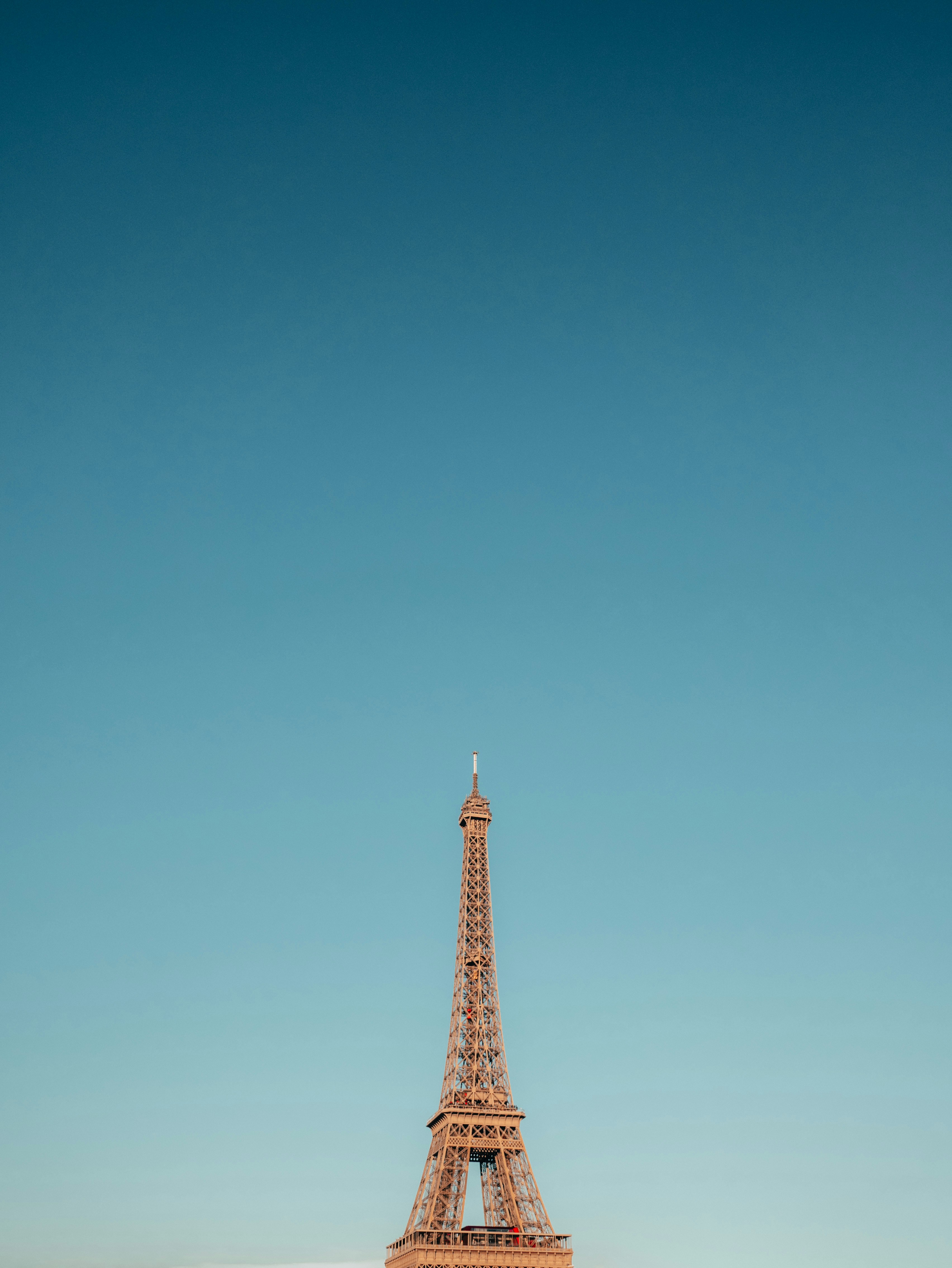 Eiffel Tower reaching into a clear blue sky, showcasing its intricate iron lattice design and grandeur.