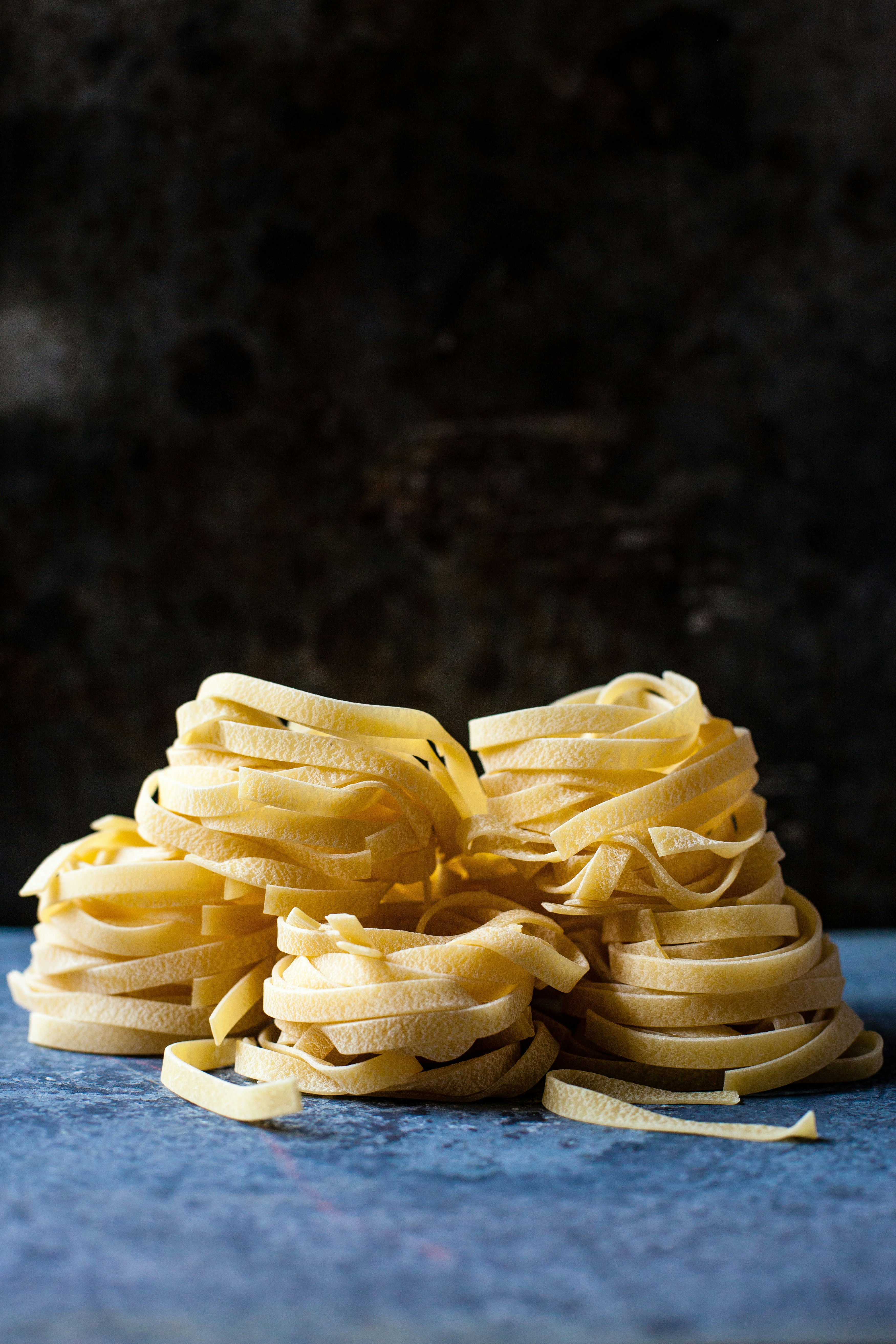 Stacks of fresh fettuccine pasta arranged artistically against a textured backdrop.