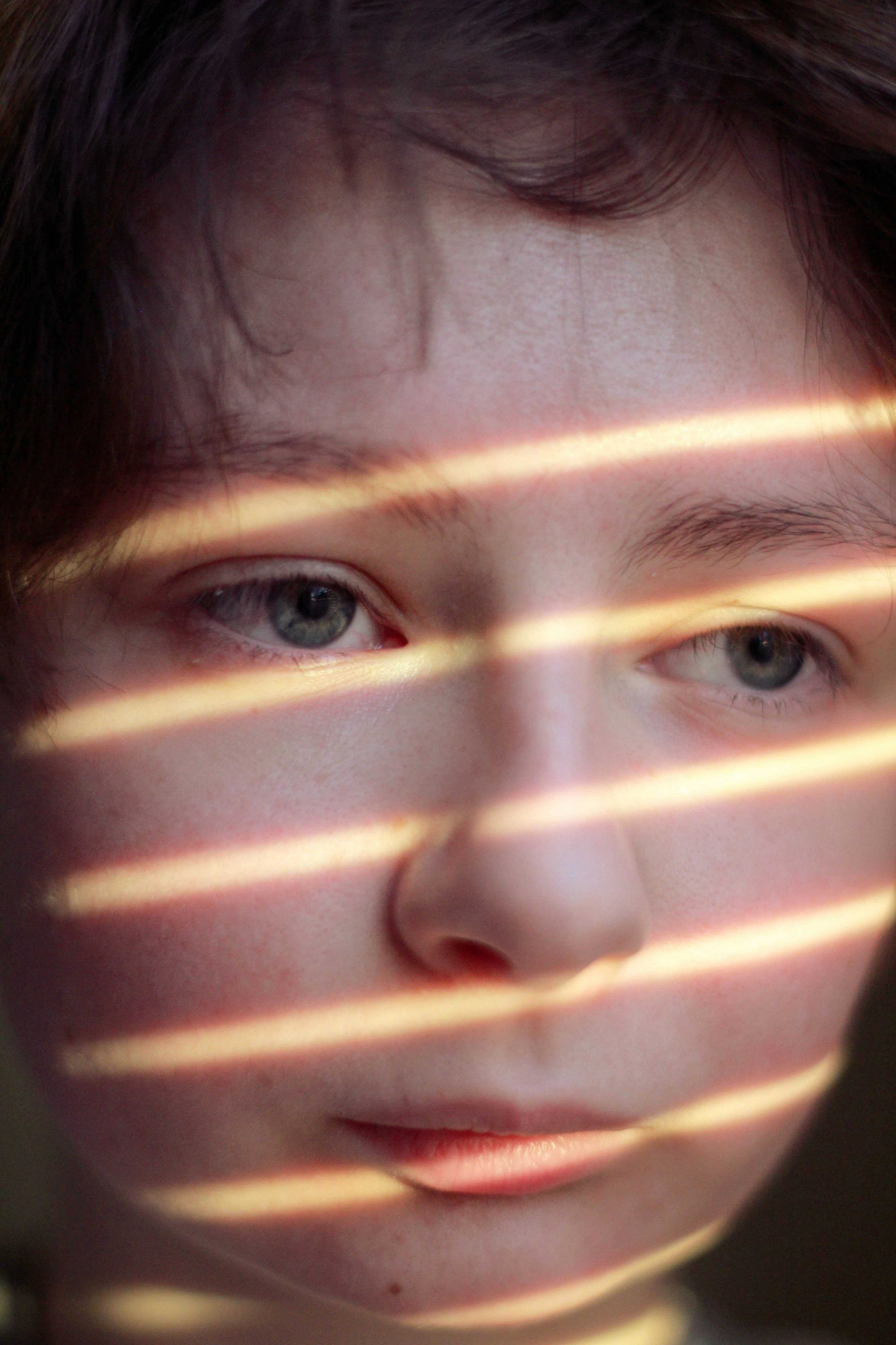 Gaze Through Striped Light: Portrait Framed by Narrow Golden Slats