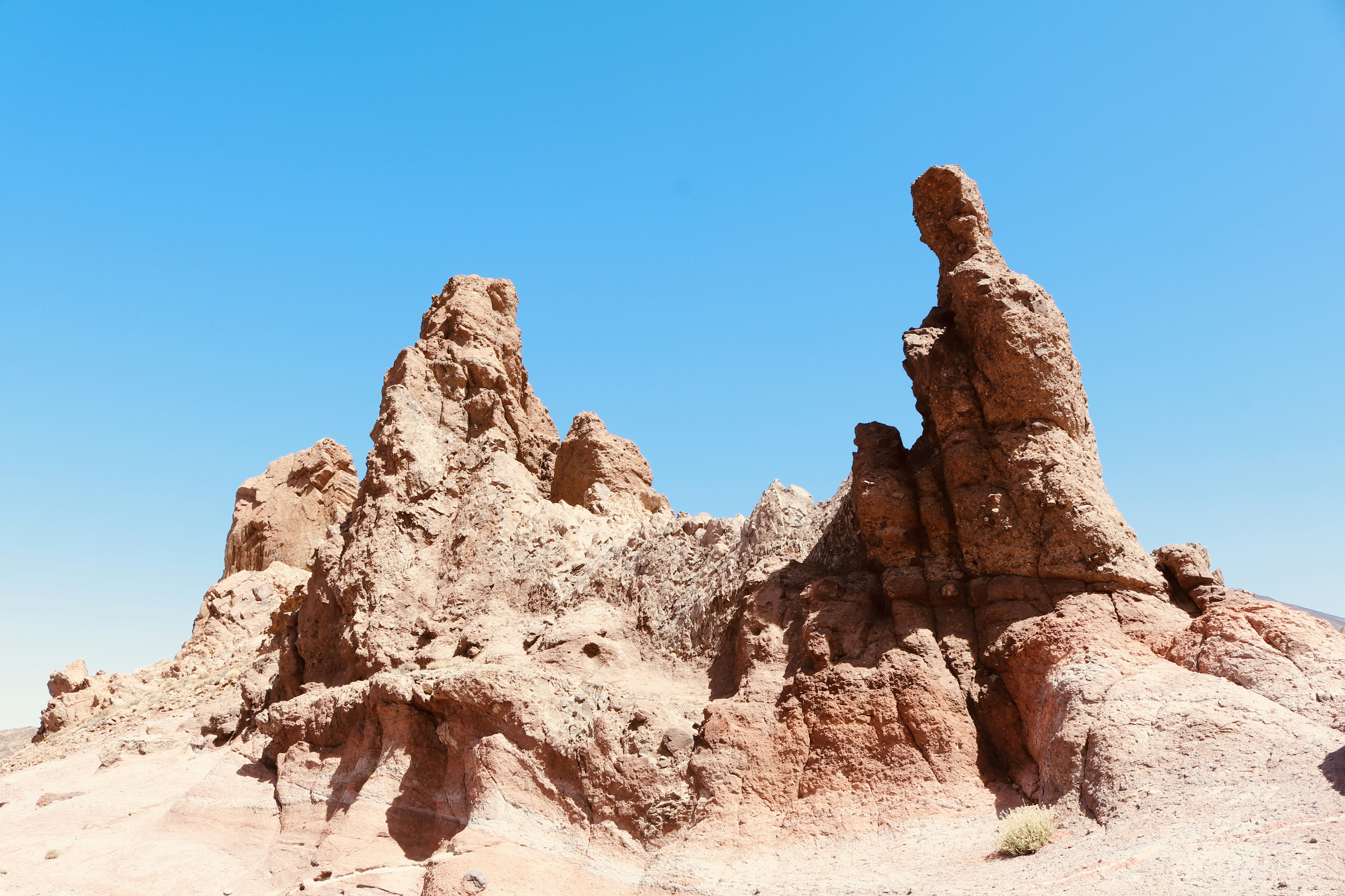 Unique rock formations rise against a clear blue sky, showcasing the intricate textures and shapes carved by nature's forces.