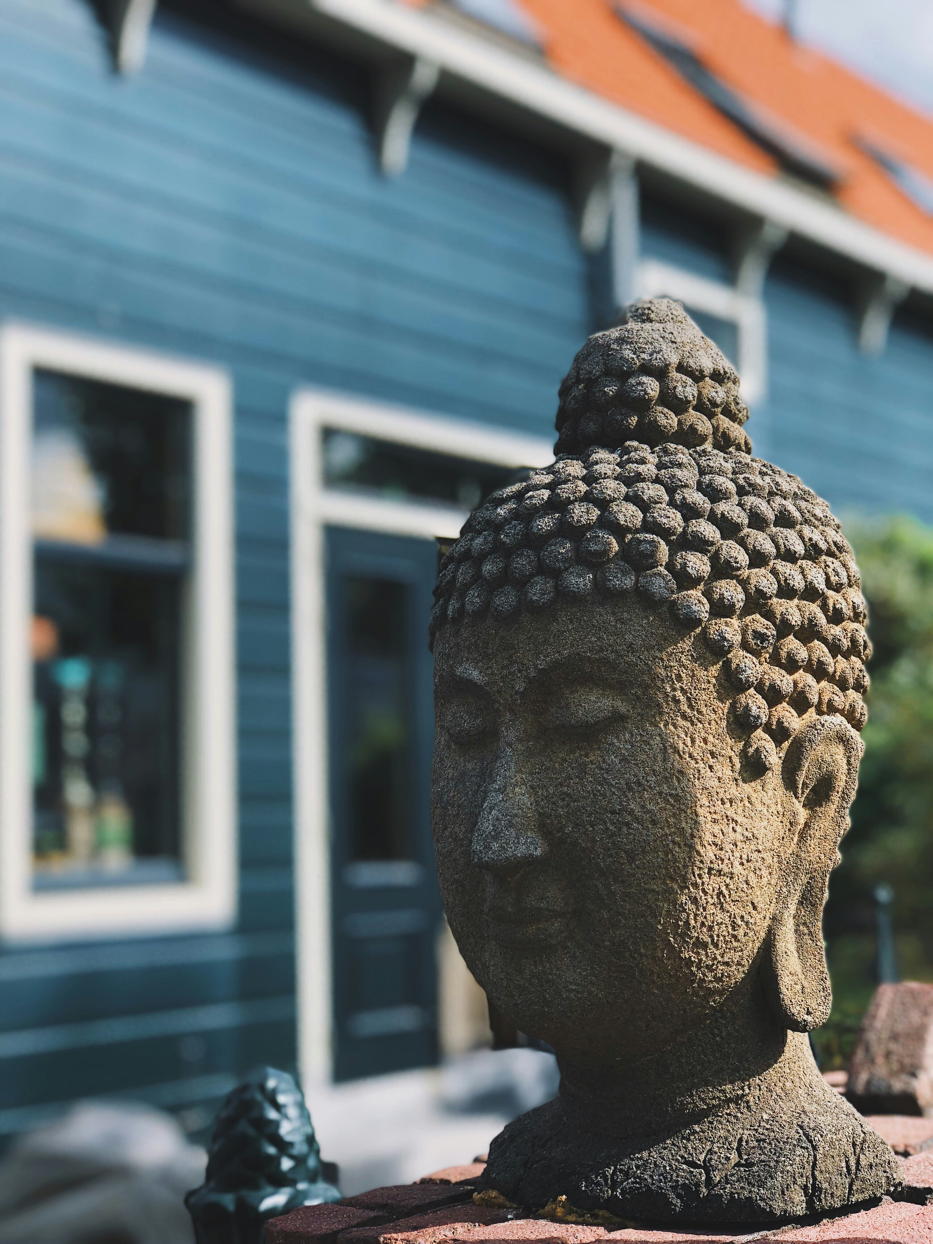 Textured Buddha Head Against a Turquoise Cottage Facade