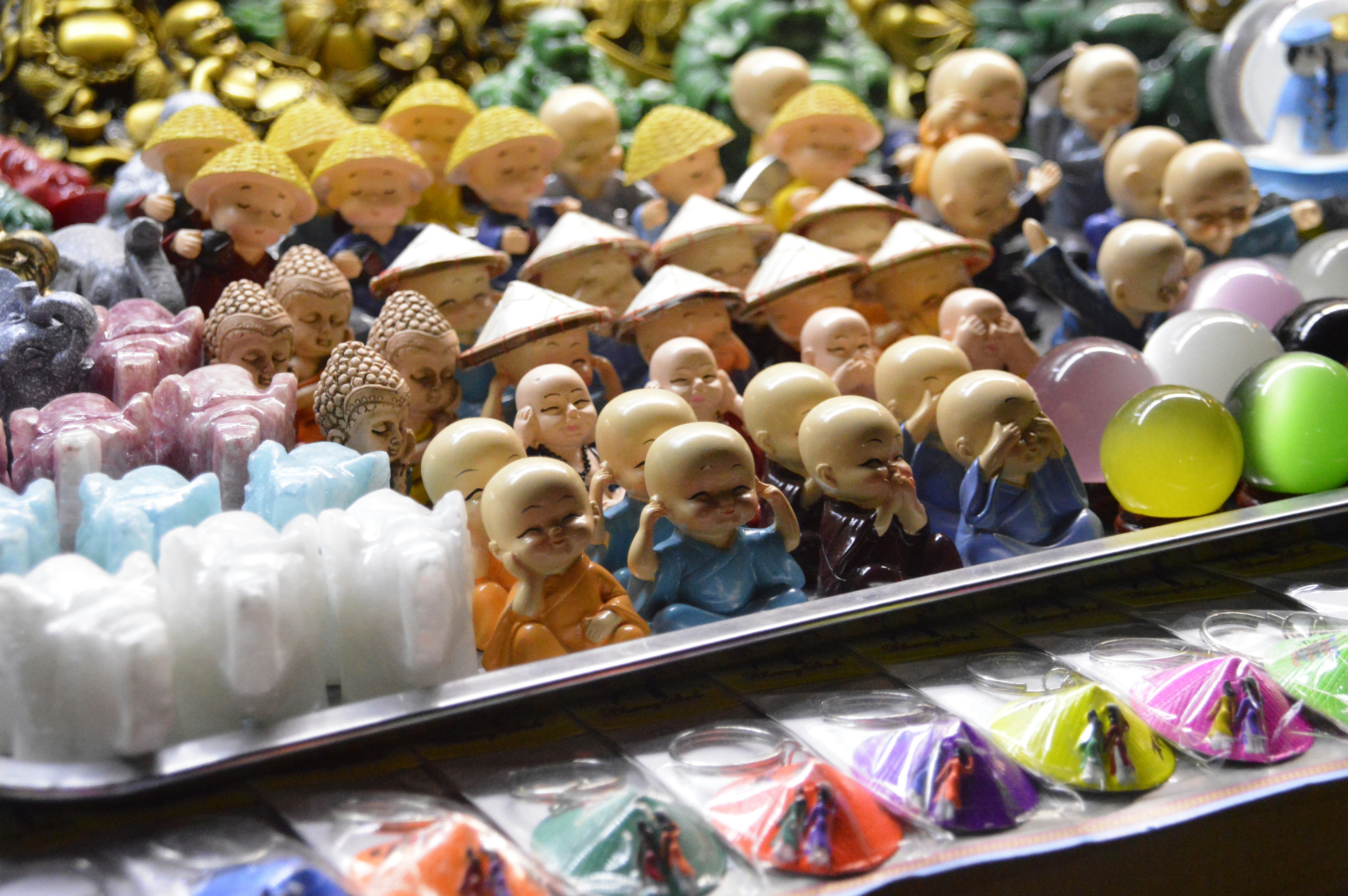 Colorful figurines of monks in various poses surrounded by vibrant trinkets on display.