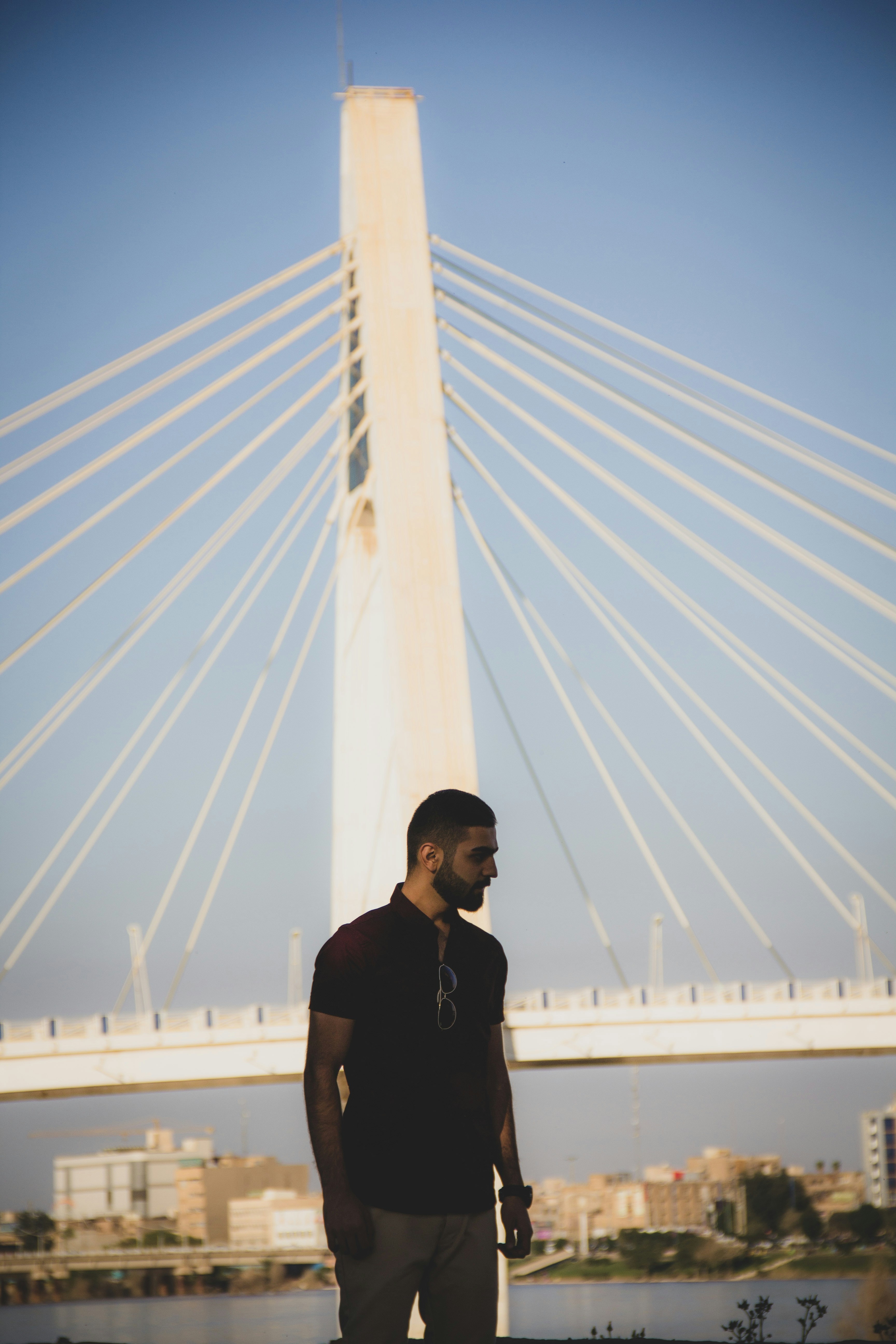 Man in foreground beneath a cable-stayed bridge at golden hour