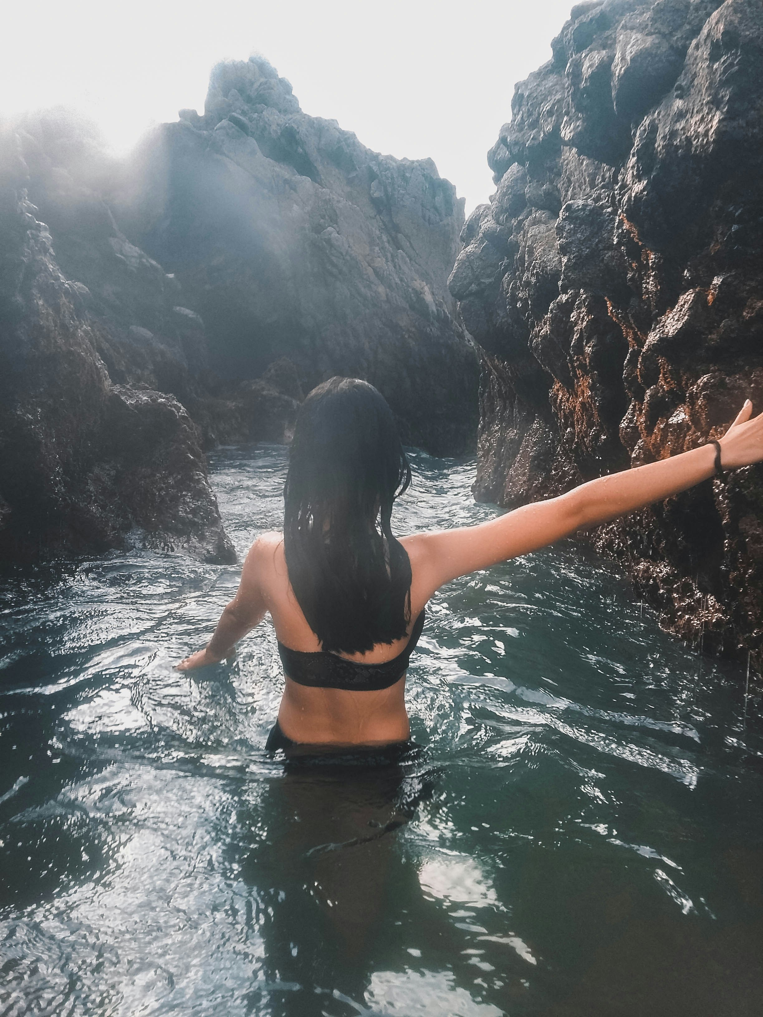 Arms Wide in a Sea-Grotto: A Solitary Swimmer Between Granite Sentinels