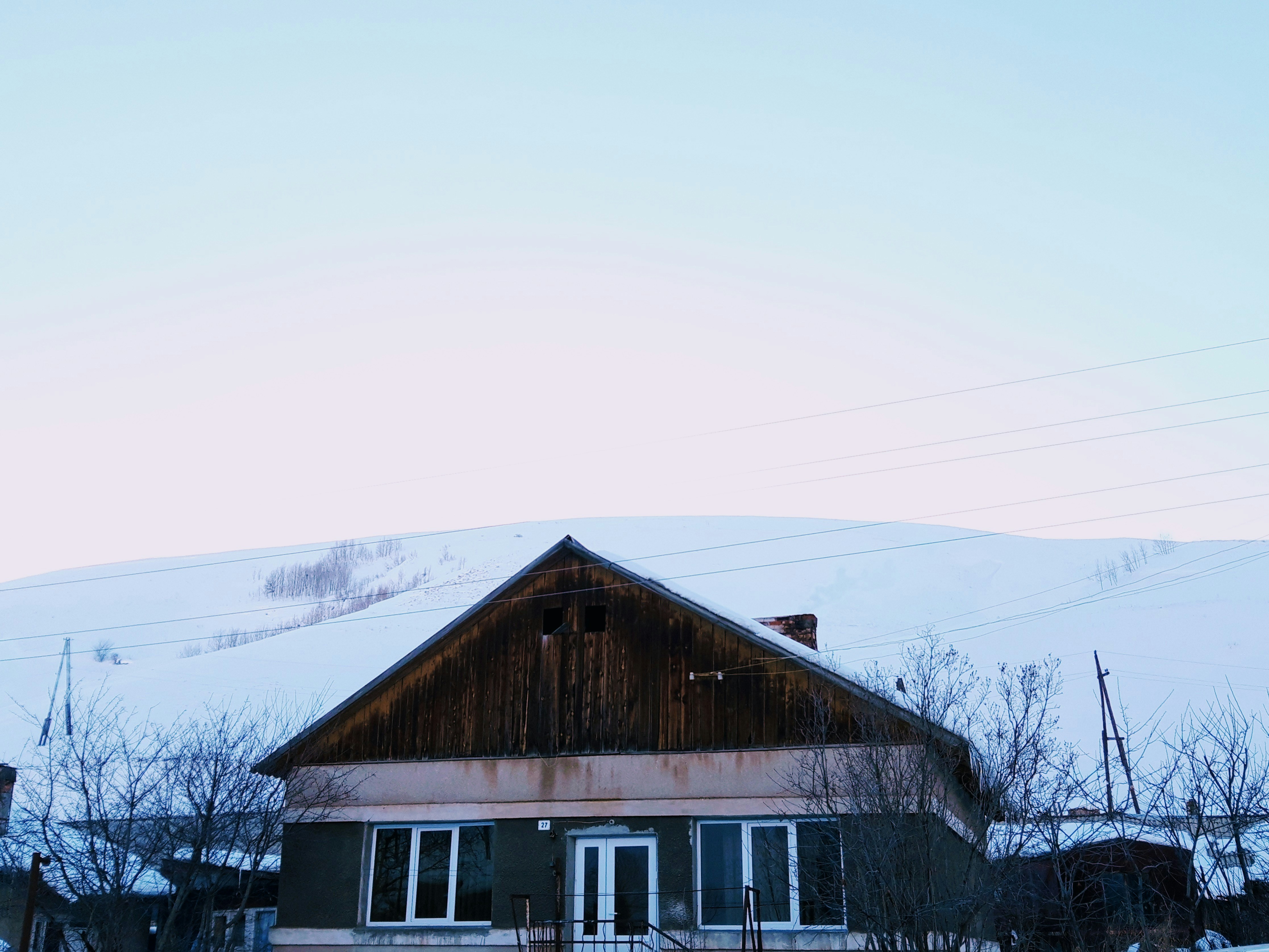 Snowbound Cottage with Weathered Wood Under a Pale Winter Sky