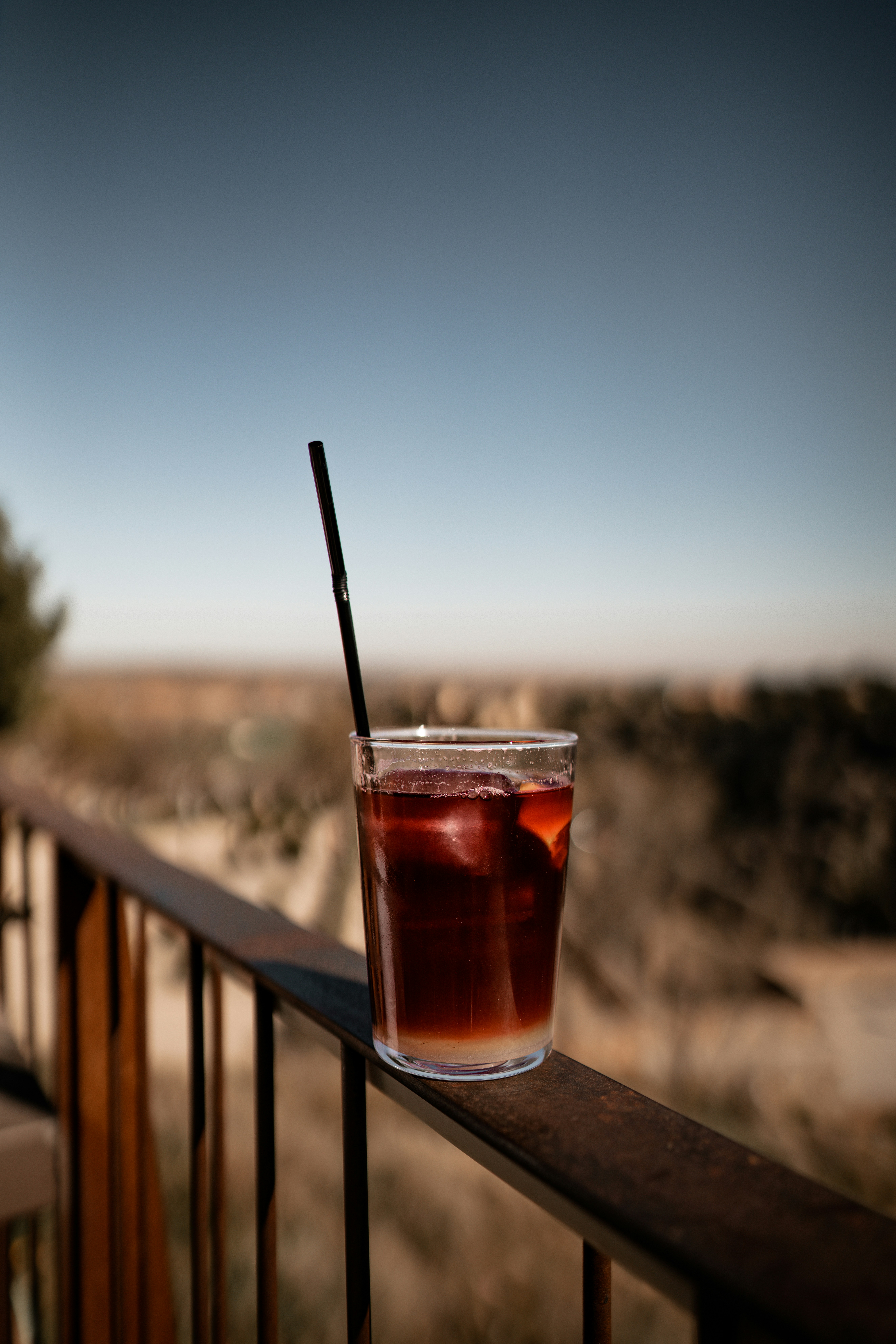 Dusk on the Rails: A Glass of Cola Graces a Sunset-Softened Balcony