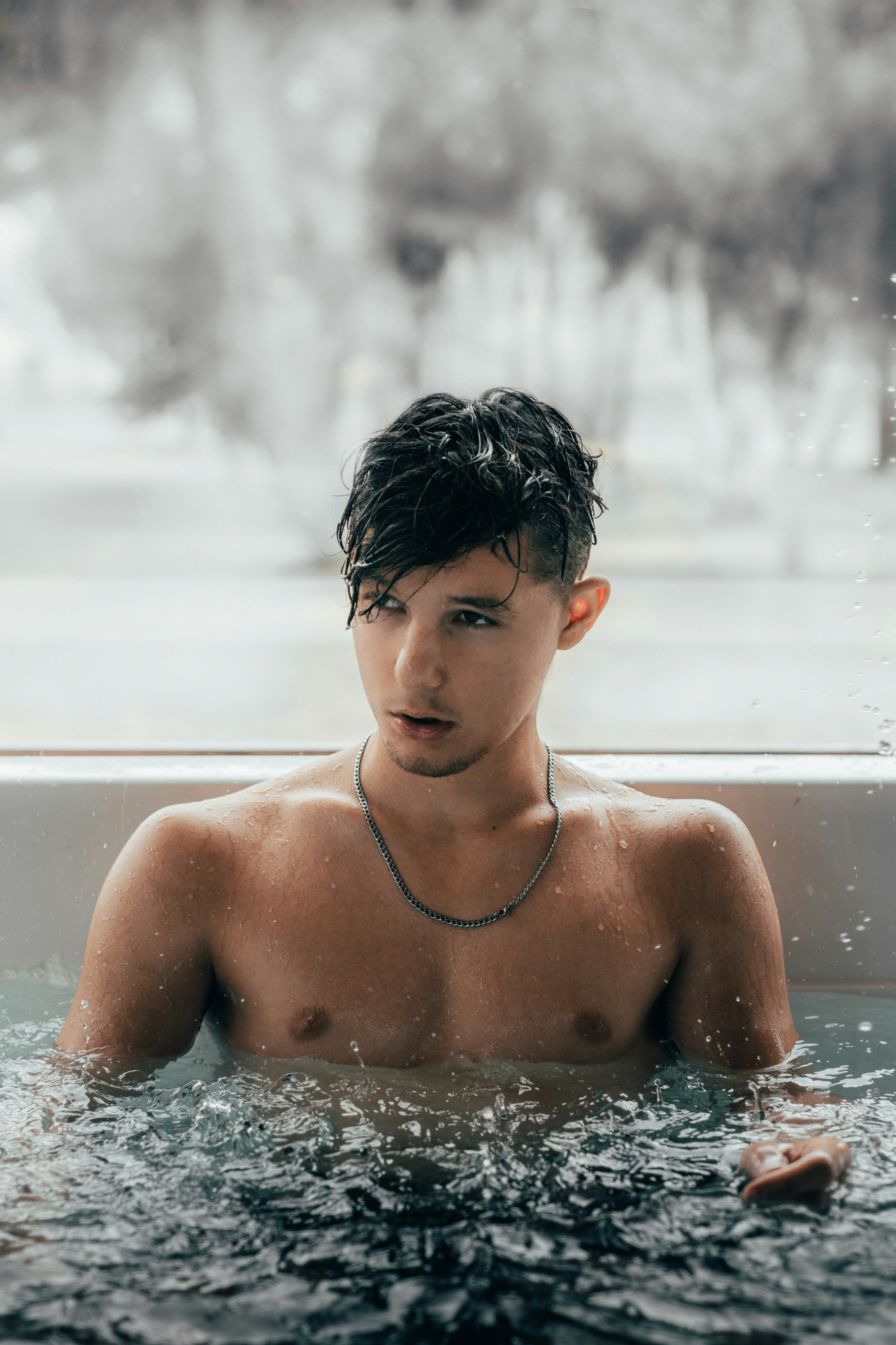 Young man relaxing in a bubbling hot tub, surrounded by soft steam and serene ambiance.