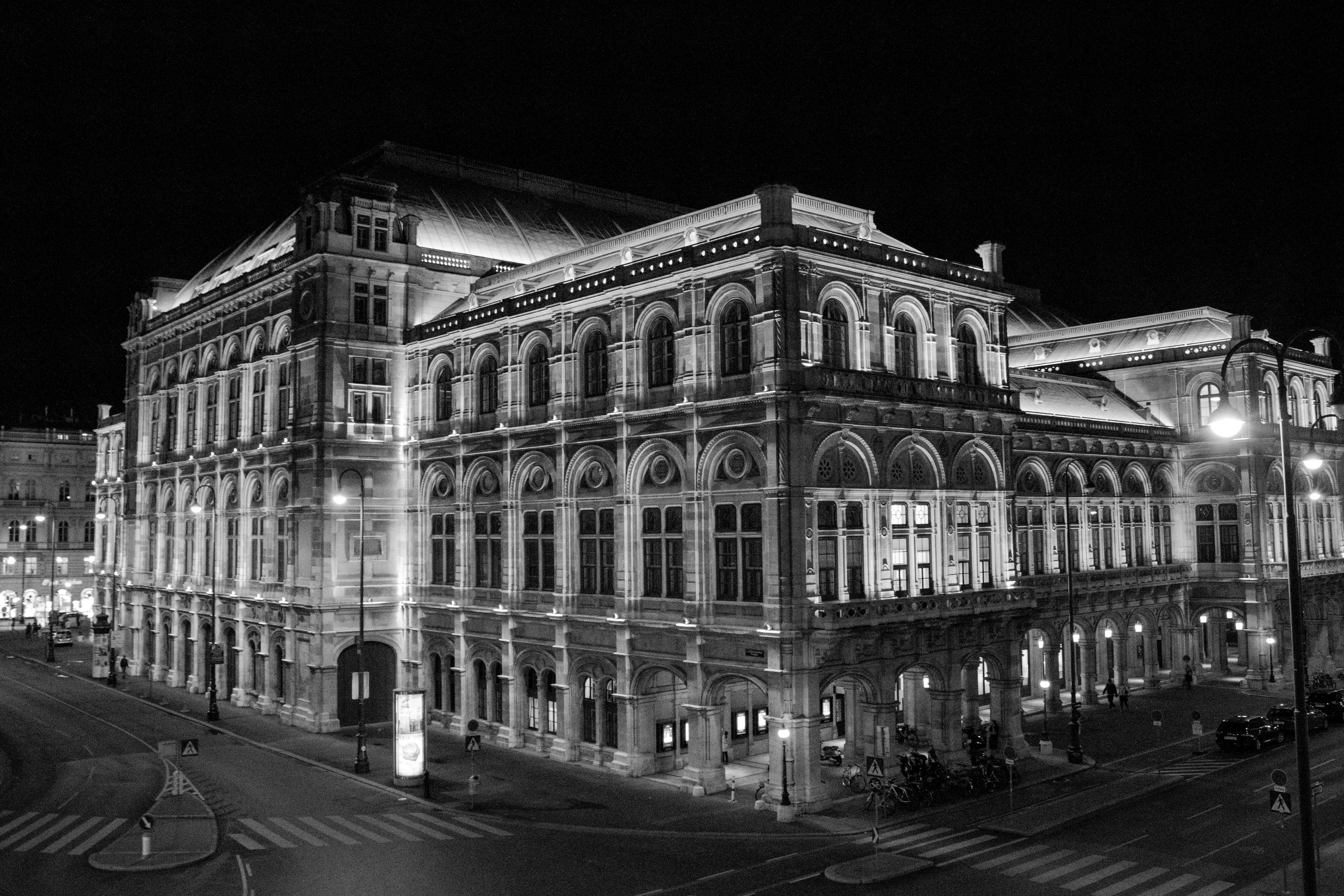 Historic theater façade illuminated at night, showcasing intricate architectural details and surrounding urban ambiance.