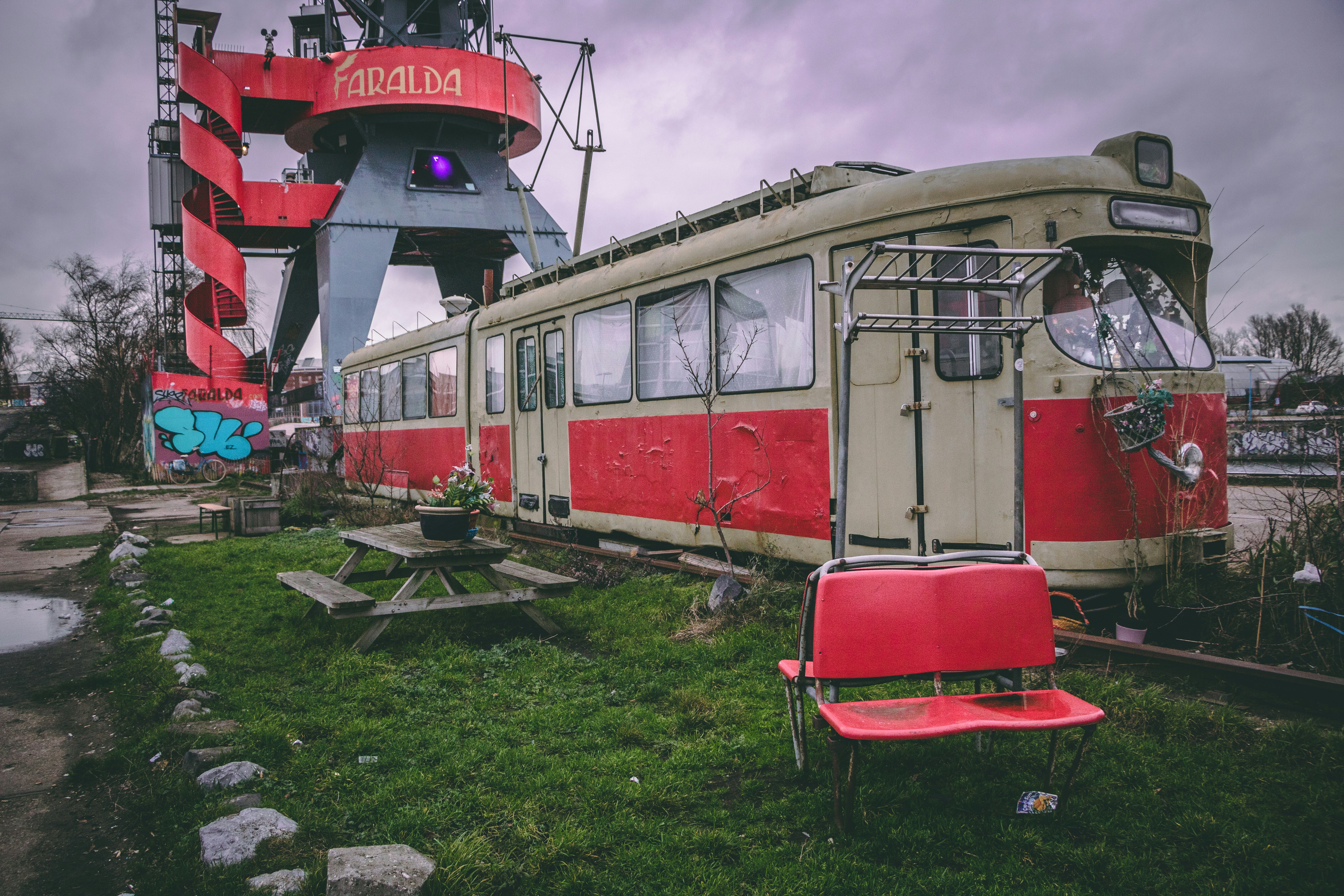 Abandoned Red Railcar by a Graffiti Arch Under a Purple Sky