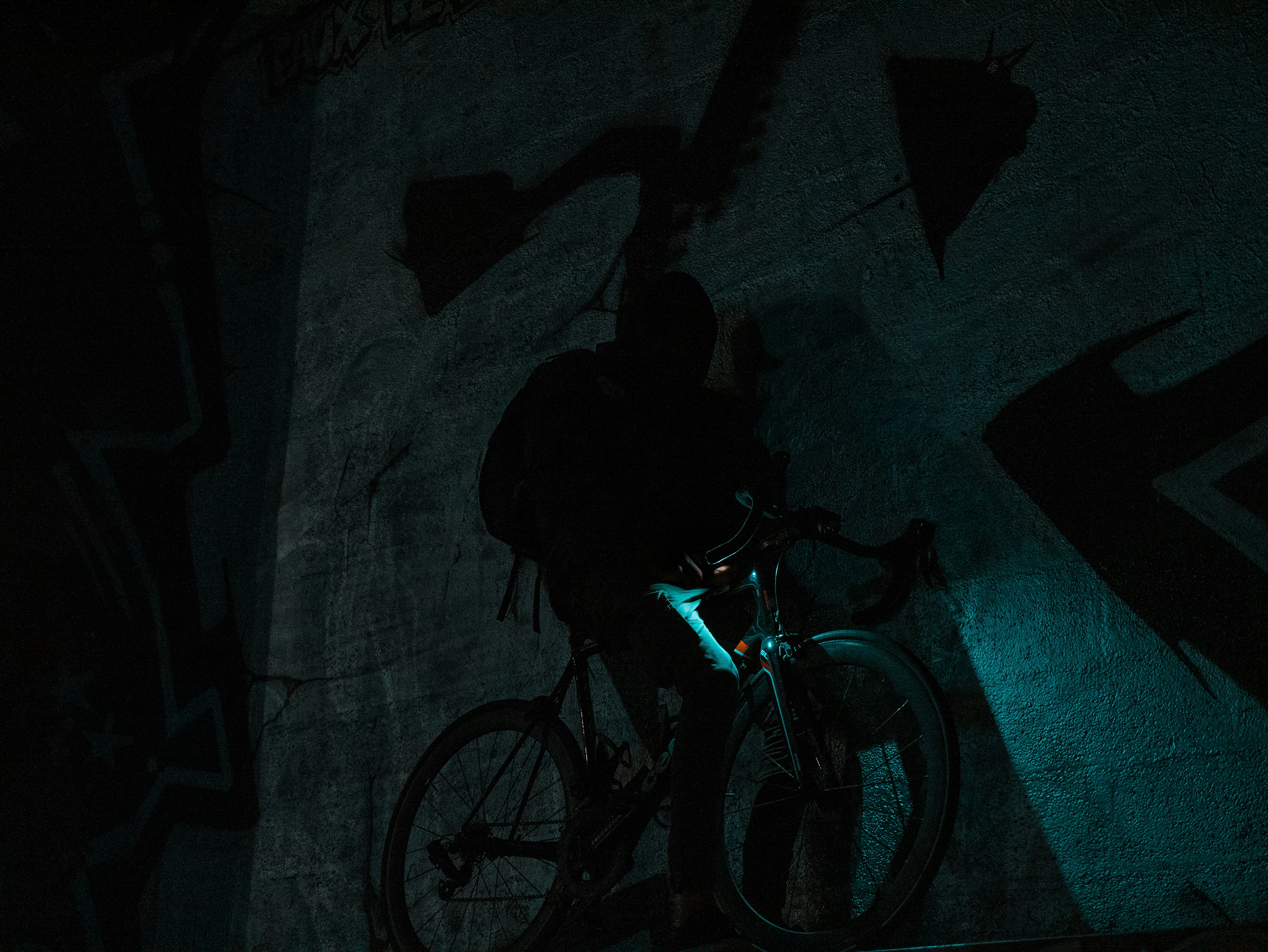 Midnight Ride: A Backlit Cyclist Emerges from Graffiti Shadows