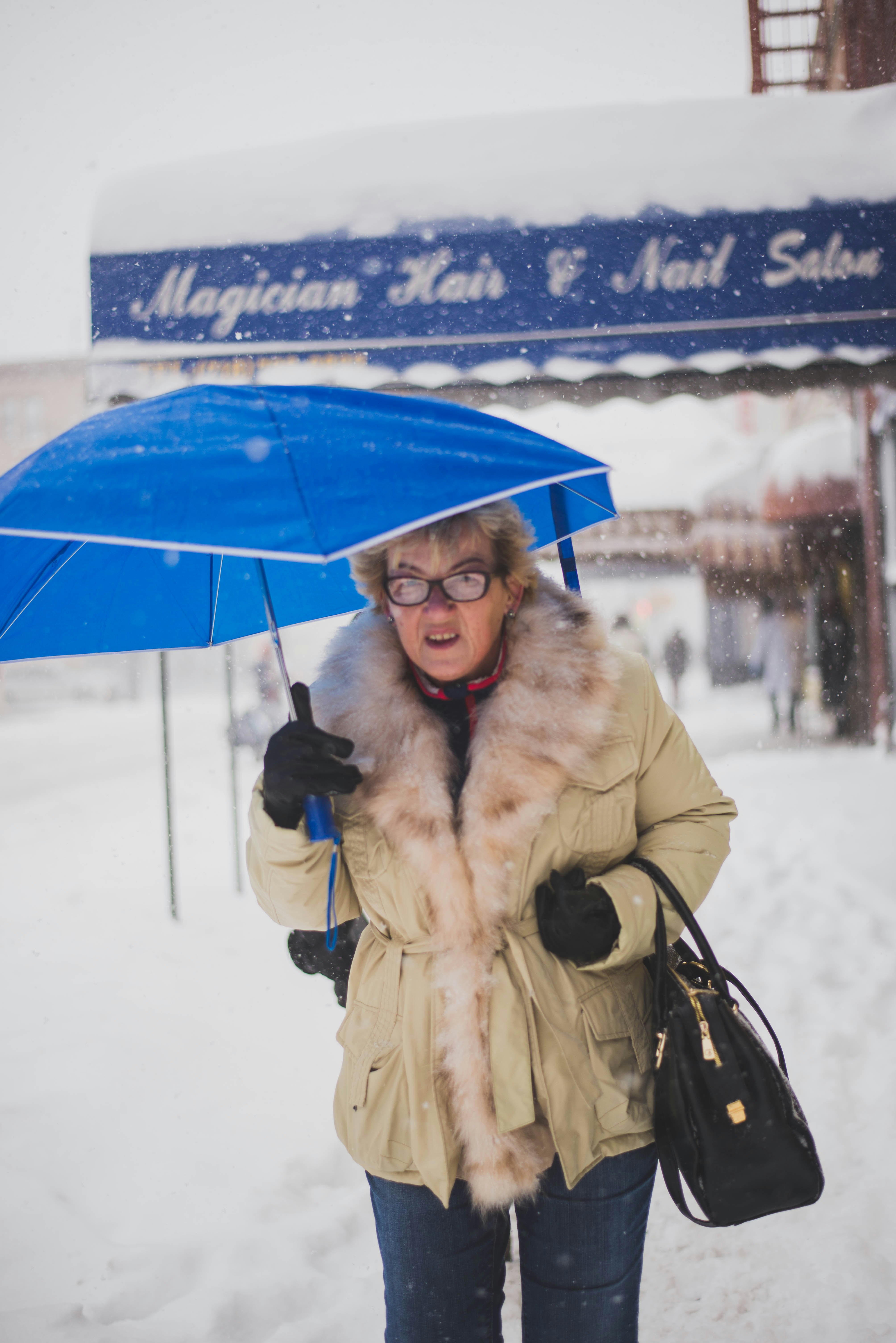 Blue Umbrella, Fur Trim, and Snow: A Pause on a Winter Street