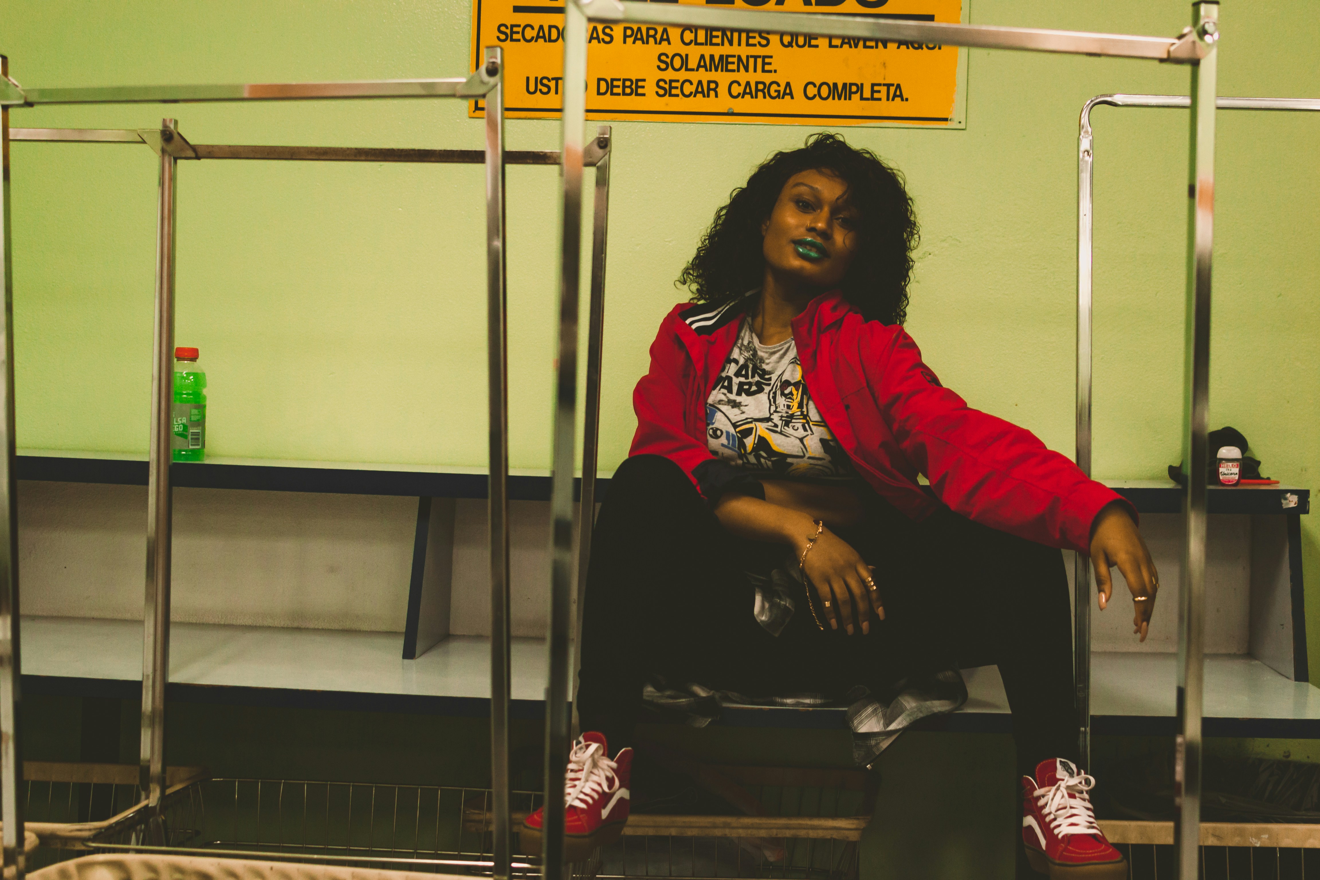Woman in red jacket sits on cubicle photo – Free Laundromat Image on ...