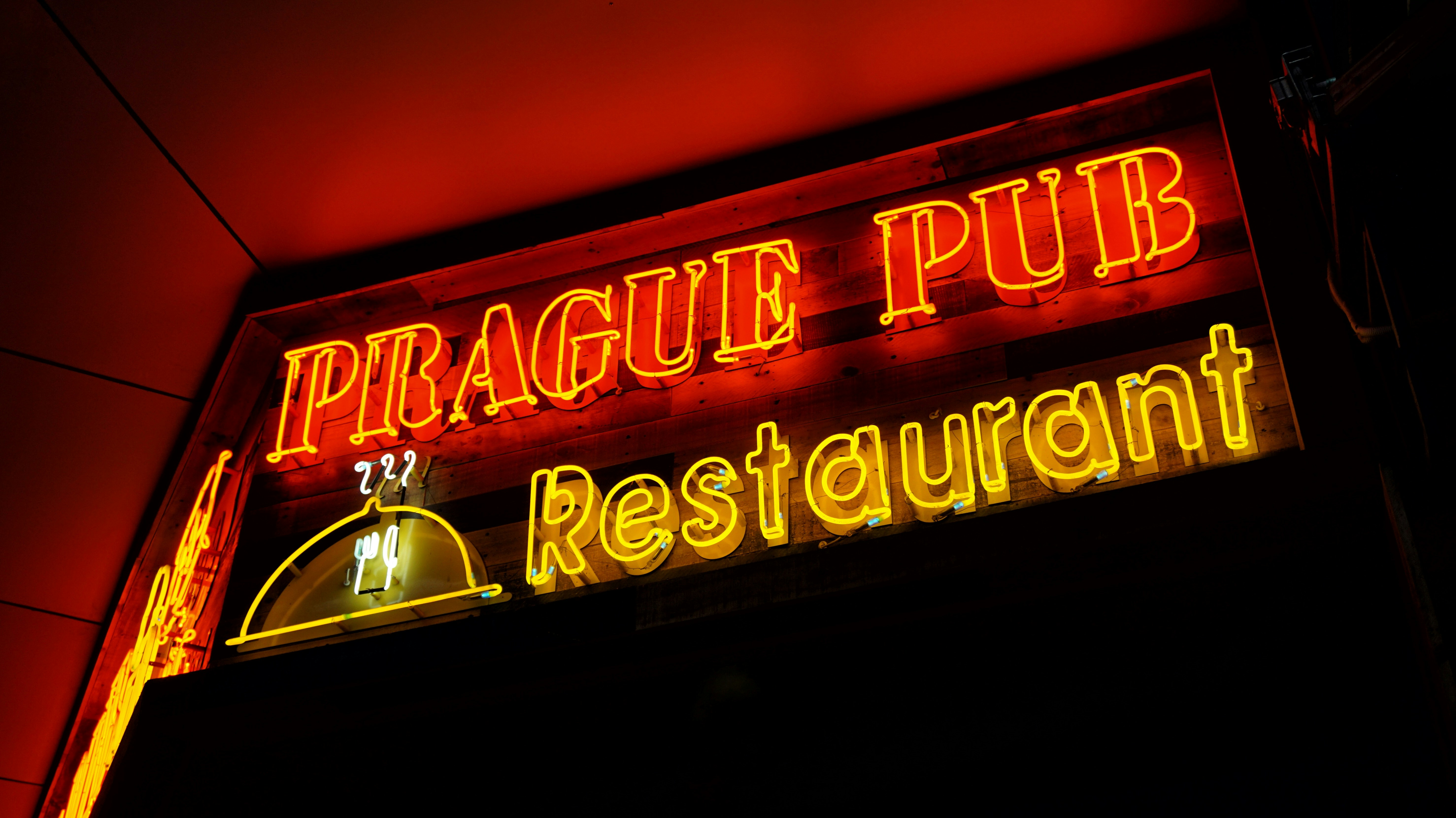 Neon Ember Over Prague Pub: Red and Amber Sign in a Dark Interior