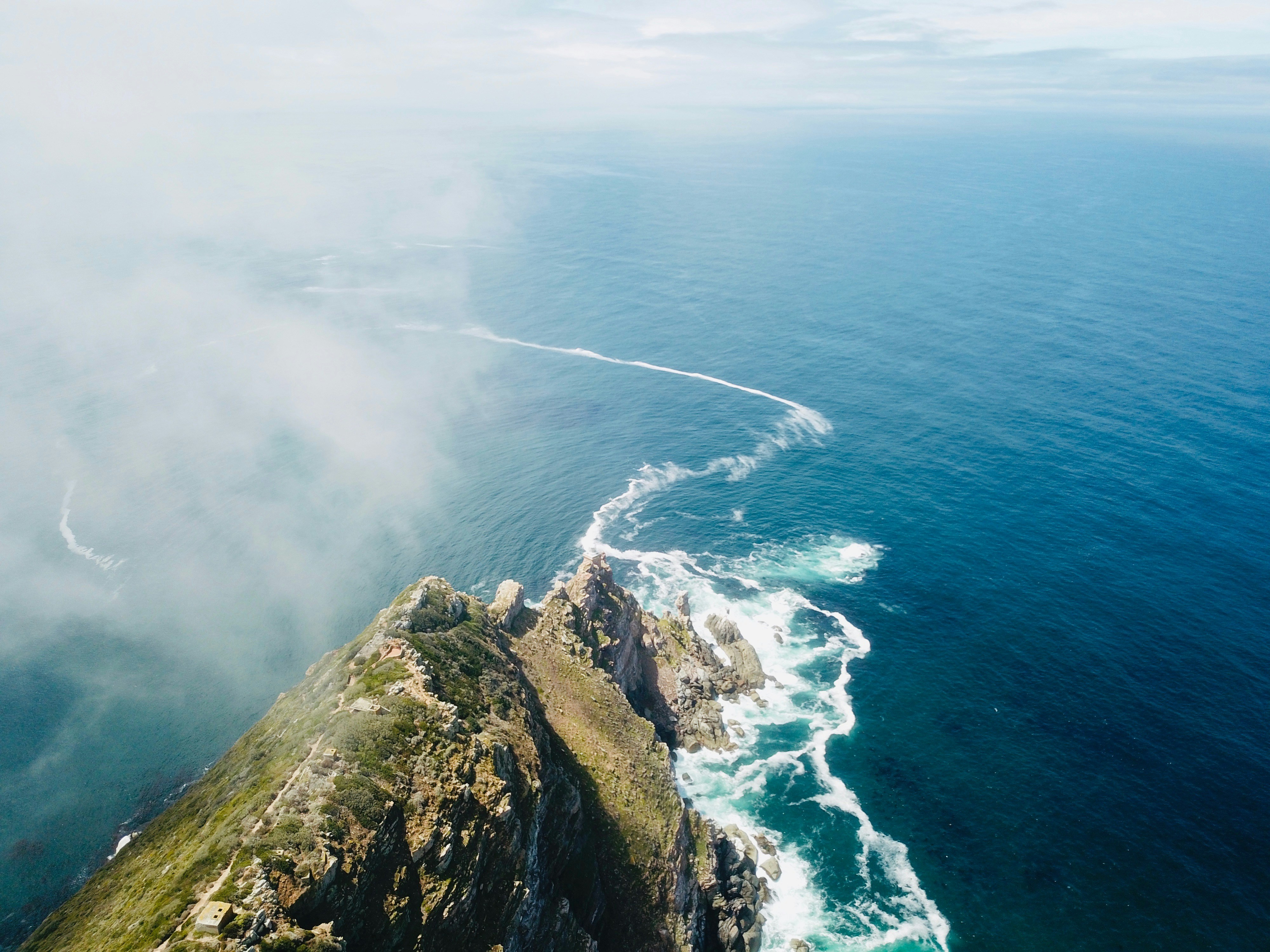 Rocky cliff jutting into the ocean under a misty sky.