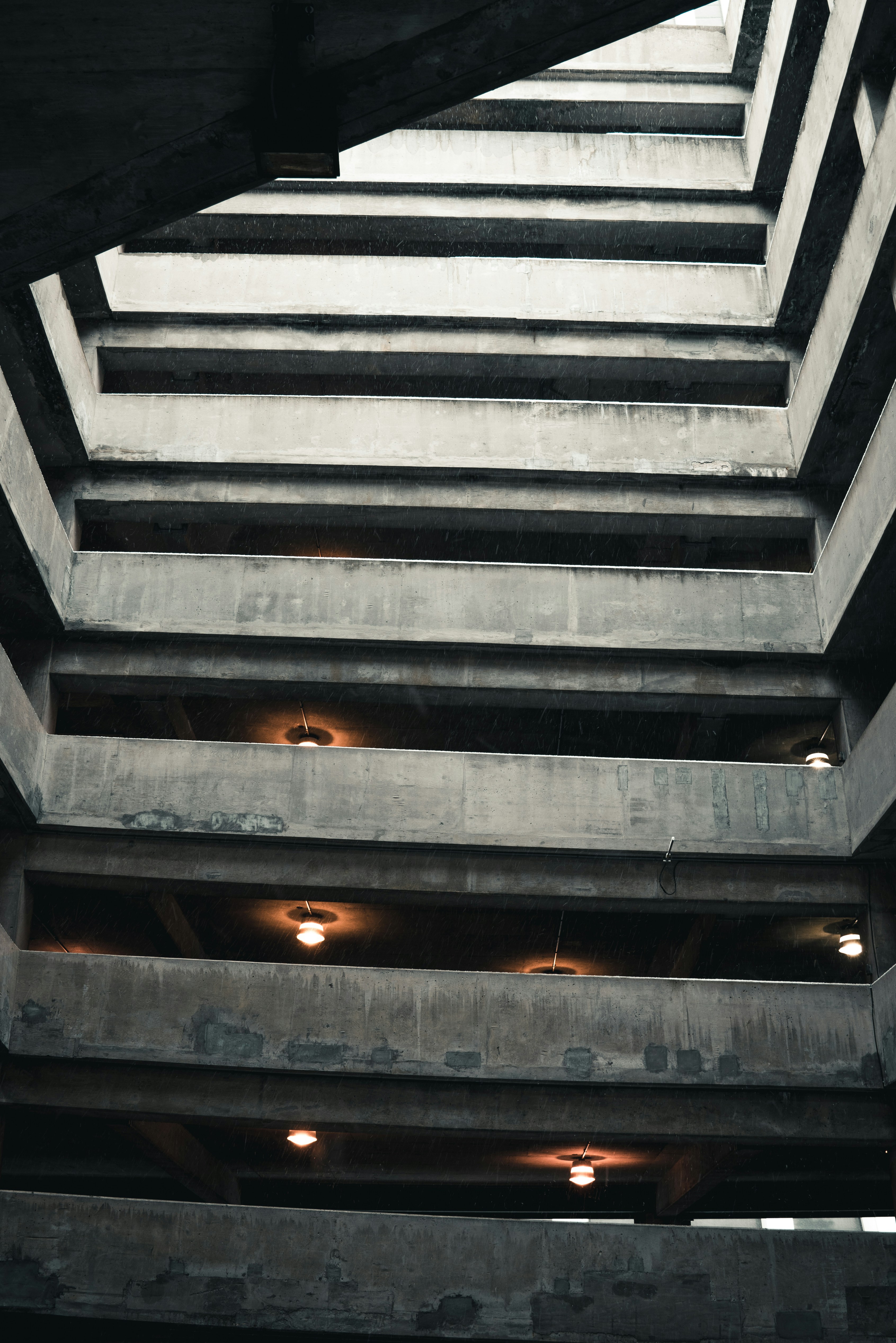 Abstract view of a concrete structure showcasing layered levels and illuminated fixtures. The interplay of light and shadow creates a dramatic architectural composition.