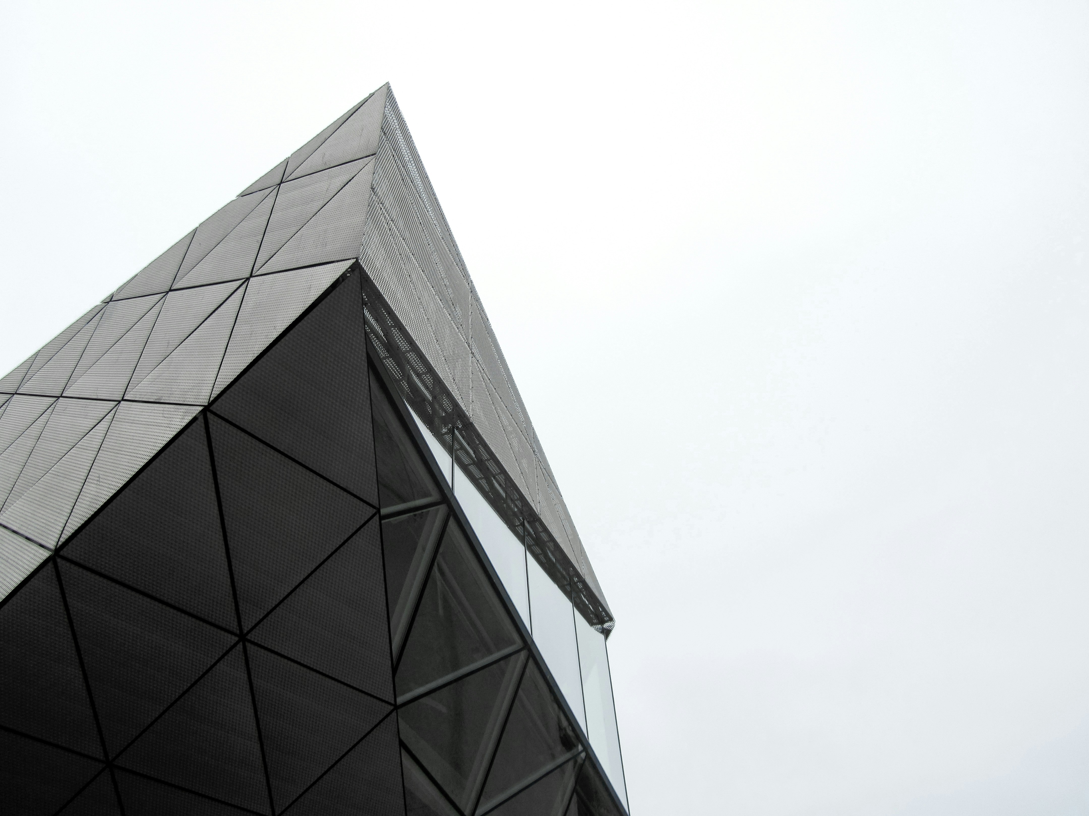 Angular modern architecture with reflective glass panels under a cloudy sky.