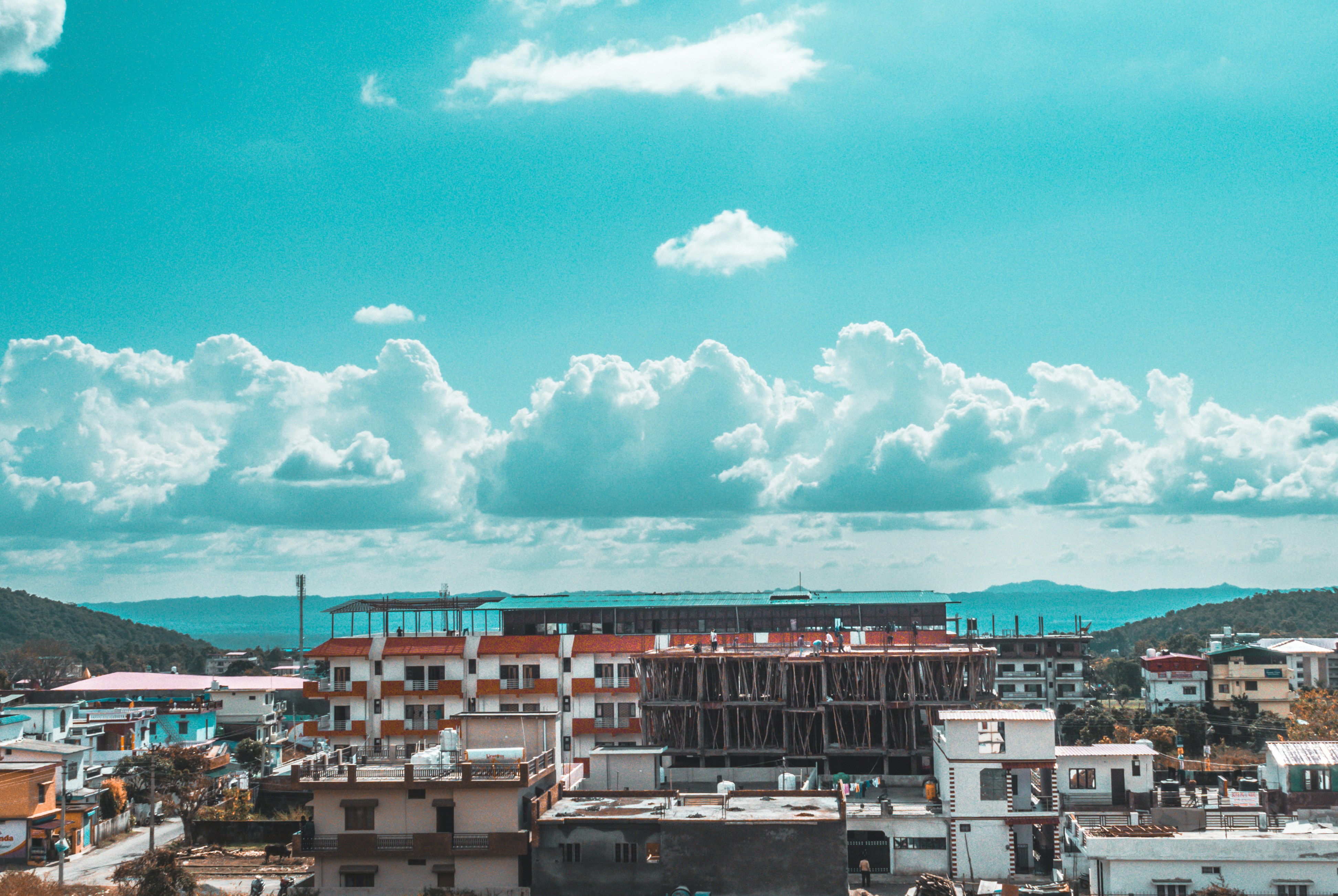 Vibrant urban landscape featuring a mix of residential buildings and construction under a dramatic sky filled with fluffy clouds.