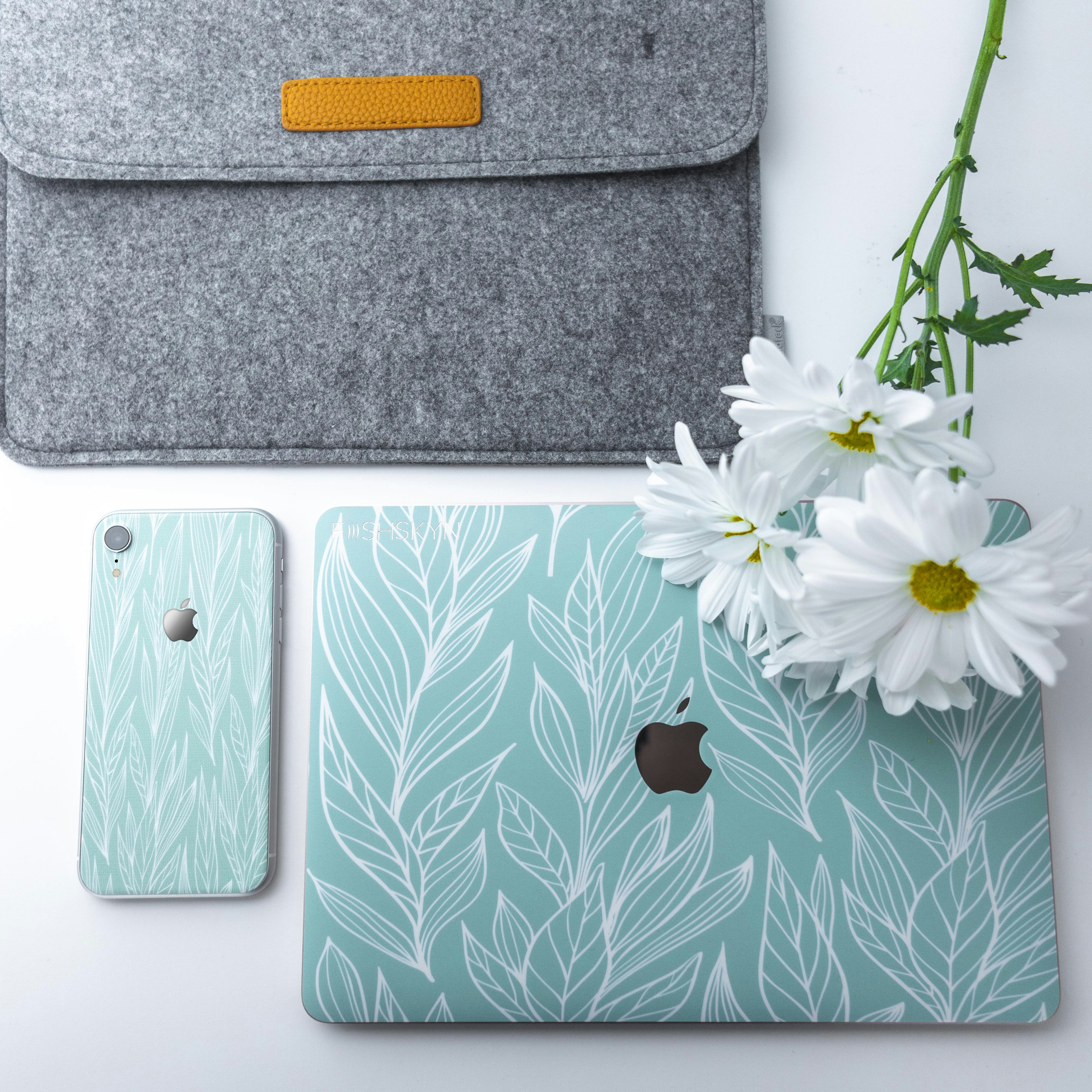 Teal Leaves on a Quiet Desk: A Laptop, Phone, and Daisies Still Life