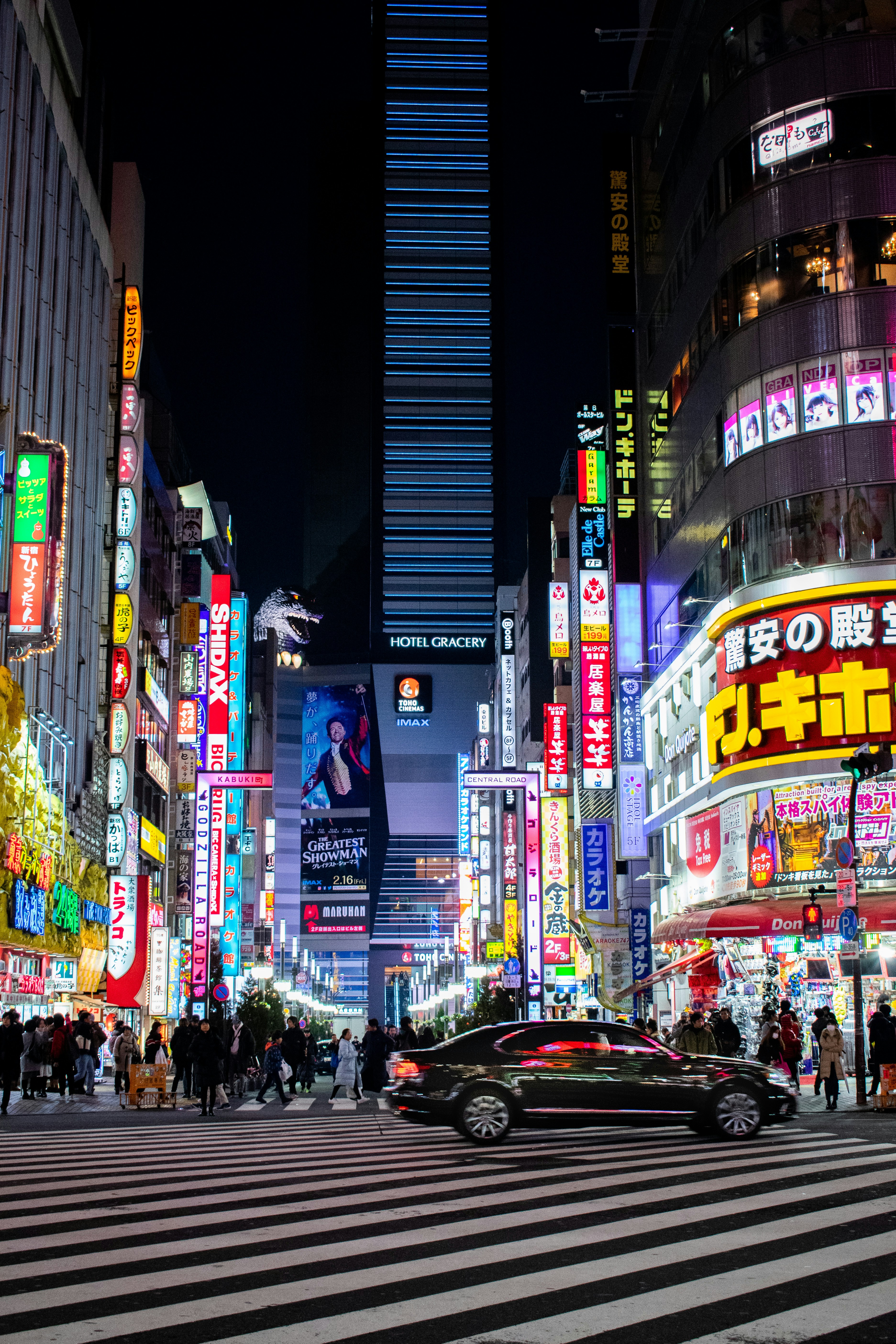 Vibrant city intersection illuminated by colorful neon signs, showcasing bustling nightlife and urban energy.