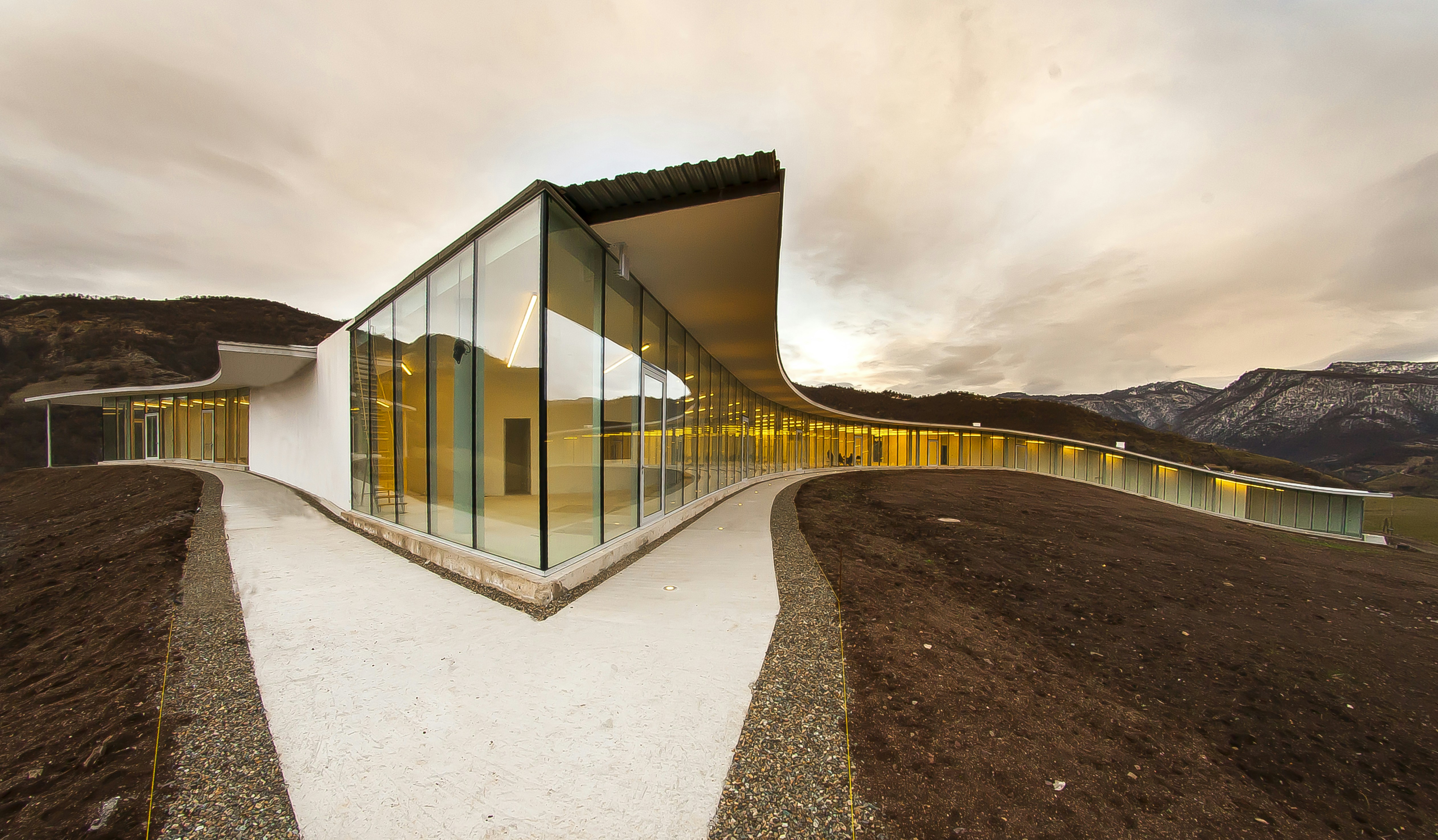 Curved Glass at Dusk: A Minimalist Pavilion in Volcanic Light