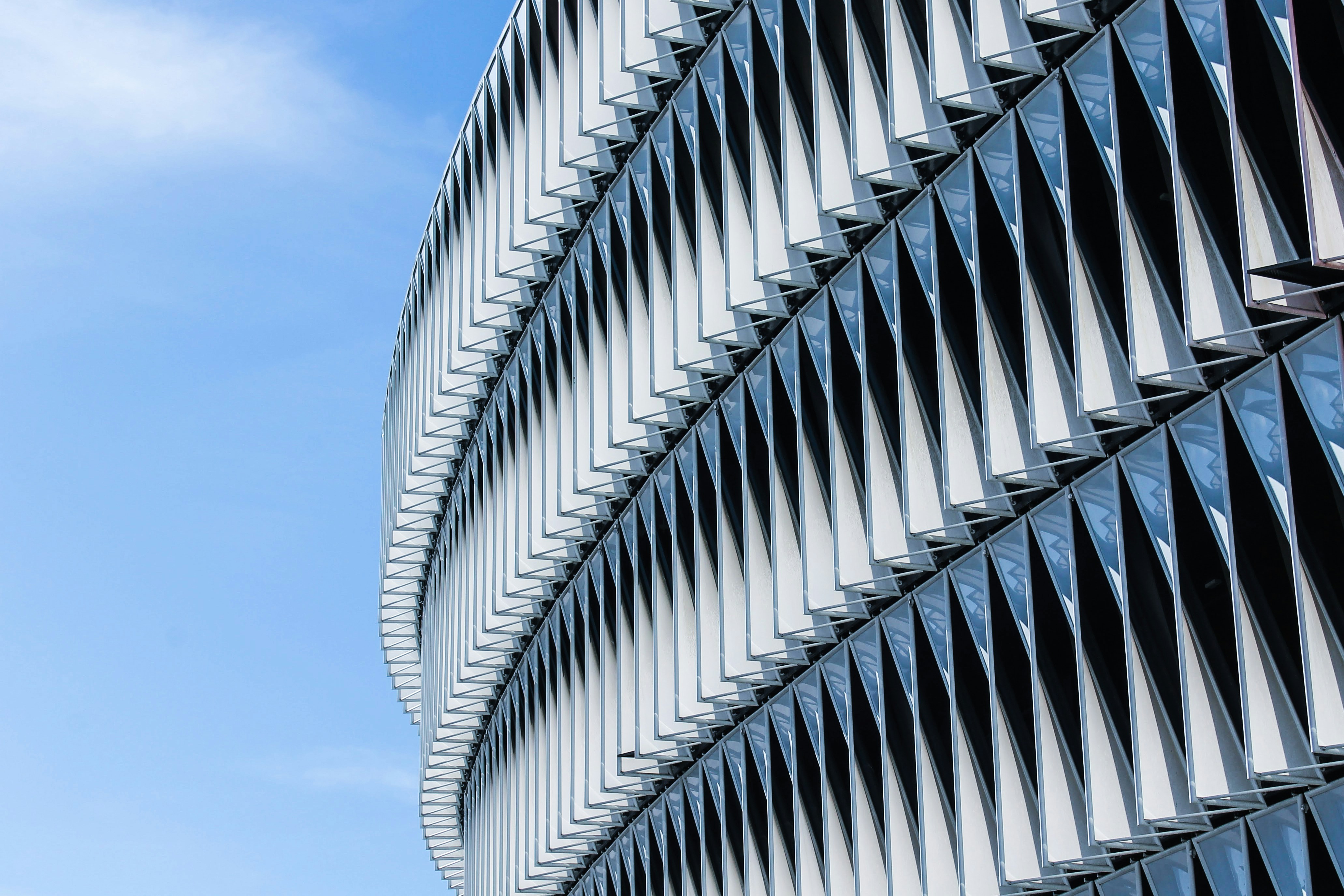 Modern building facade with repetitive triangular patterns against a clear blue sky.