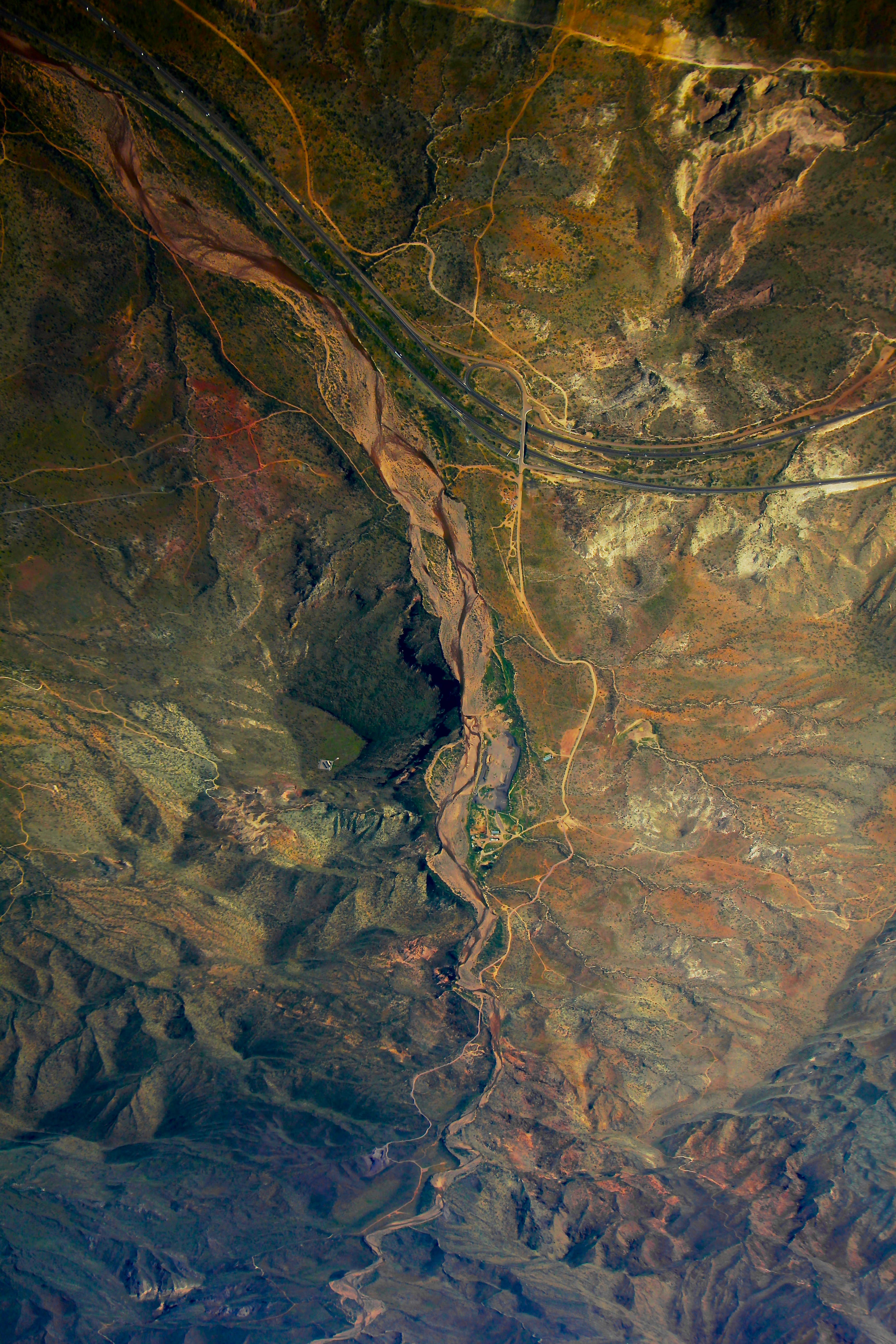 Aerial view of rugged terrain showcasing winding roads and natural formations, highlighting the interplay of land and human infrastructure.