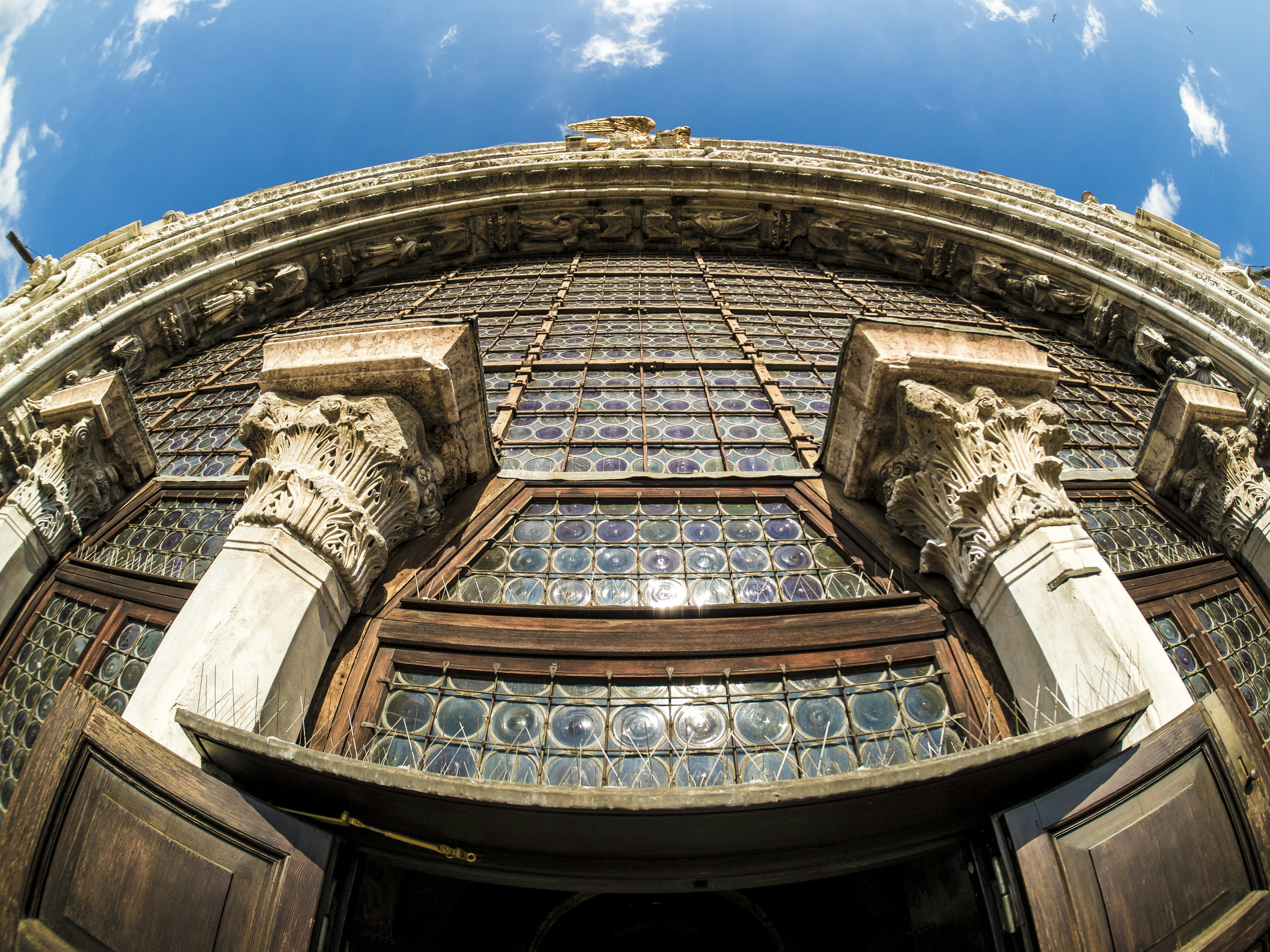 Intricate stained glass windows framed by ornate stone columns, showcasing a historical architectural masterpiece.