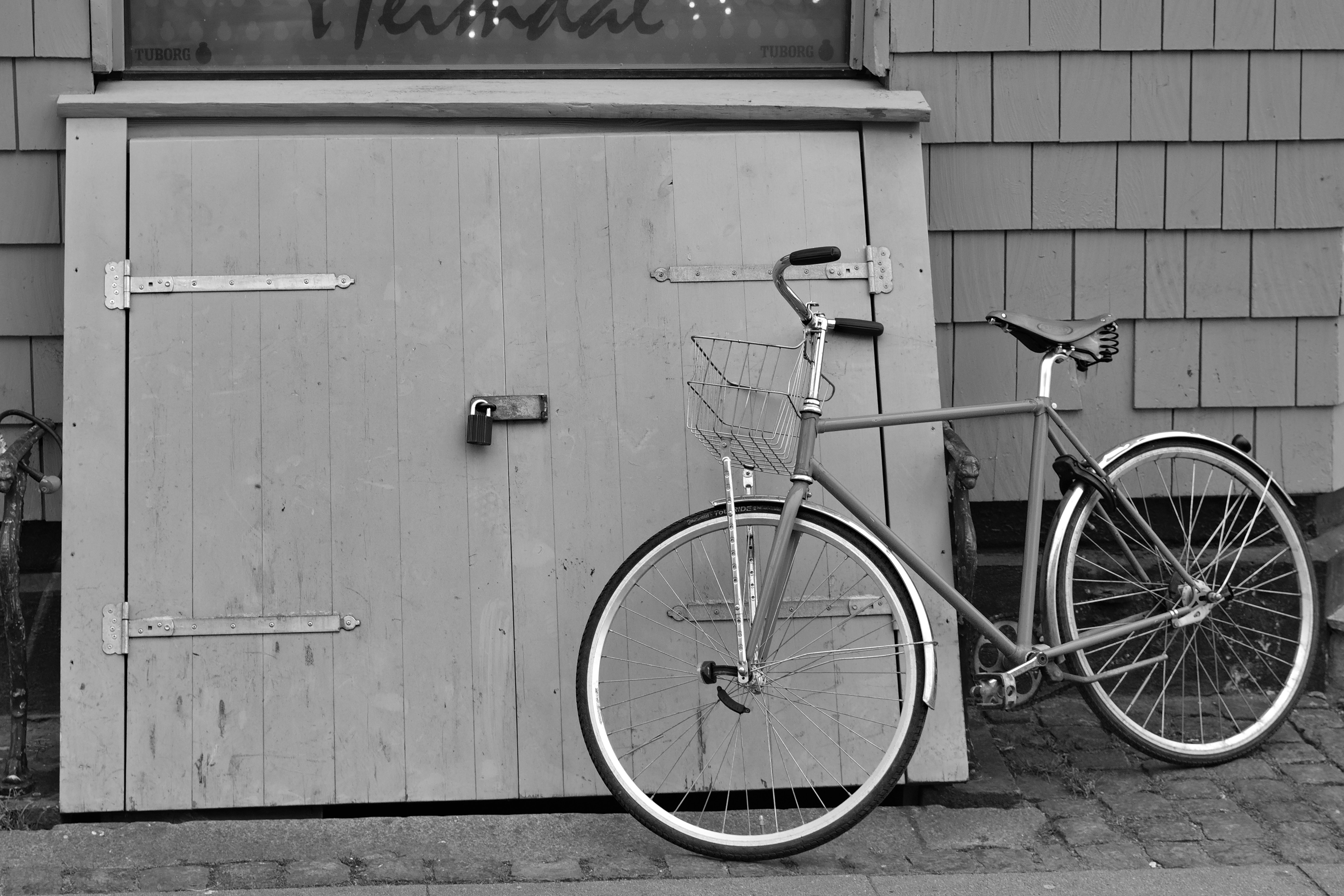 A vintage bicycle leans against a weathered wooden shed, showcasing a blend of urban life and nostalgia.
