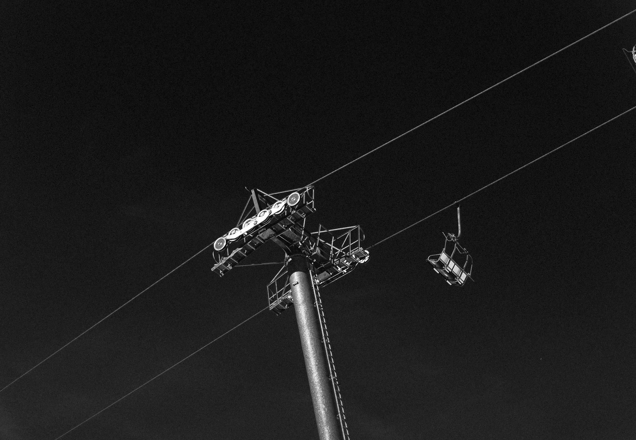 A black and white photograph showcasing a ski lift tower with gondolas suspended above, capturing the essence of winter adventures.