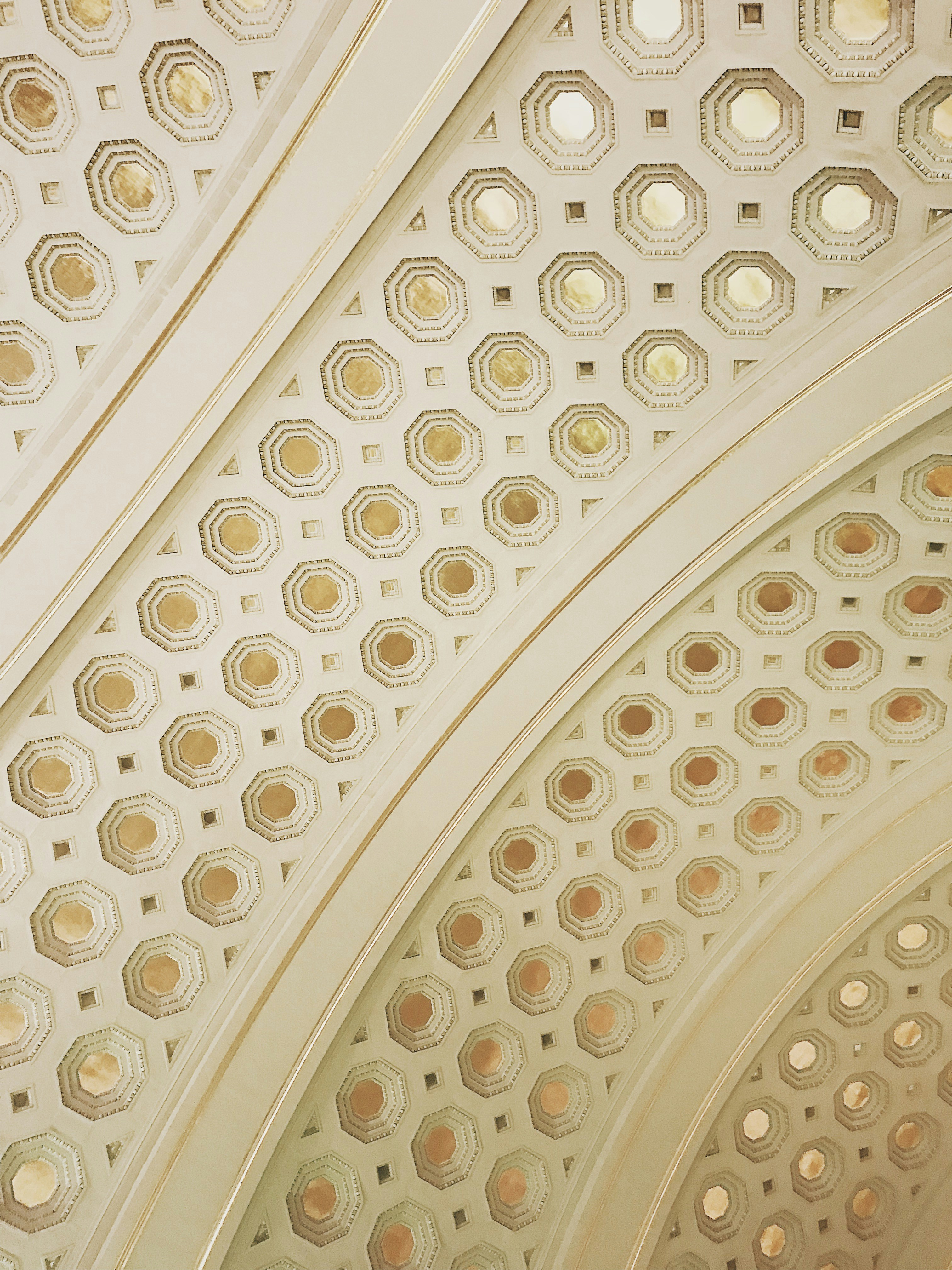 Intricate hexagonal patterns of a ceiling adorned with circular accents, showcasing elegant architectural design.