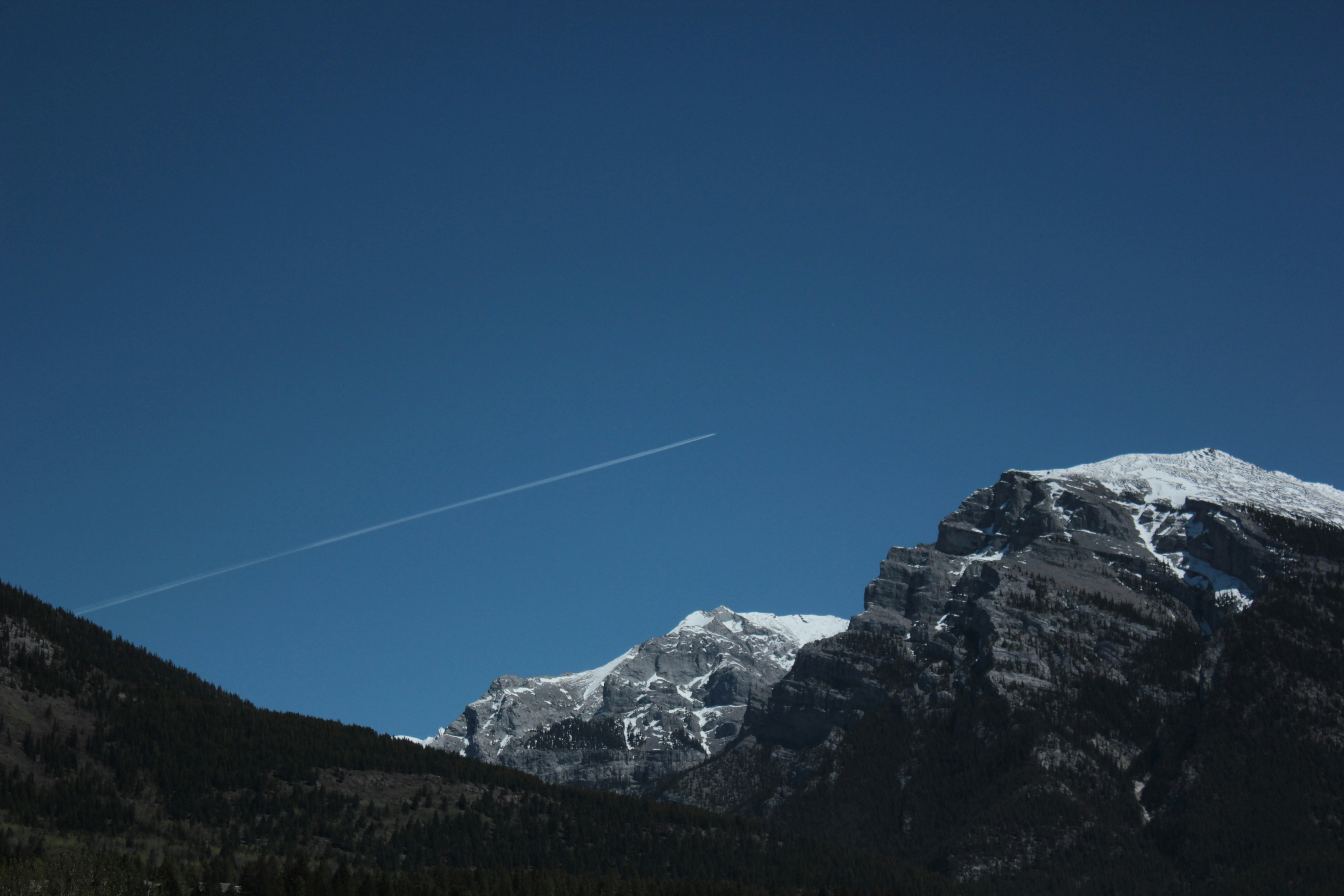 Contrail over the Crown of Snow: Alpine Peaks Under a Pristine Blue Sky