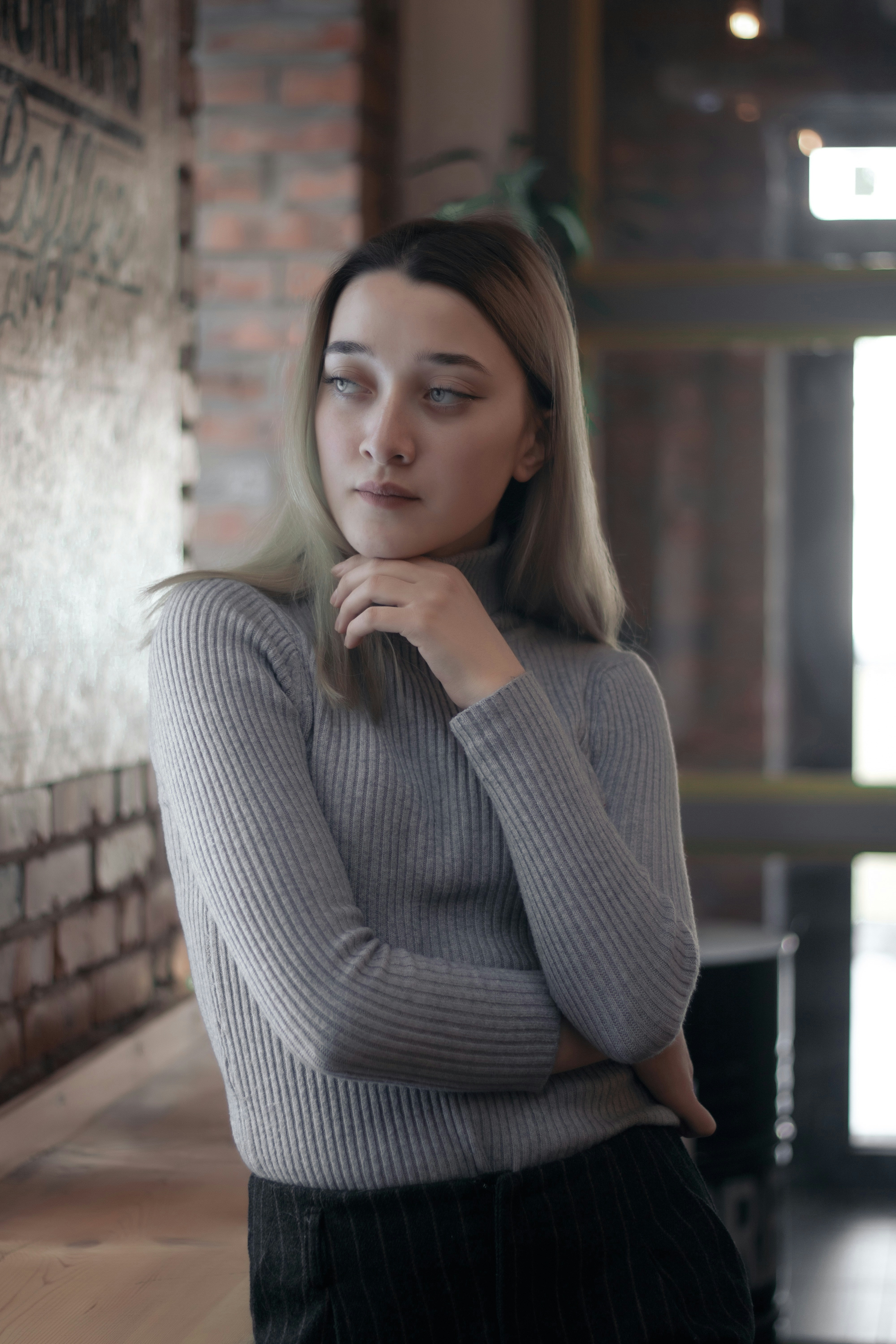 Muted Light, Thoughtful Gaze in a Brick-Walled Café