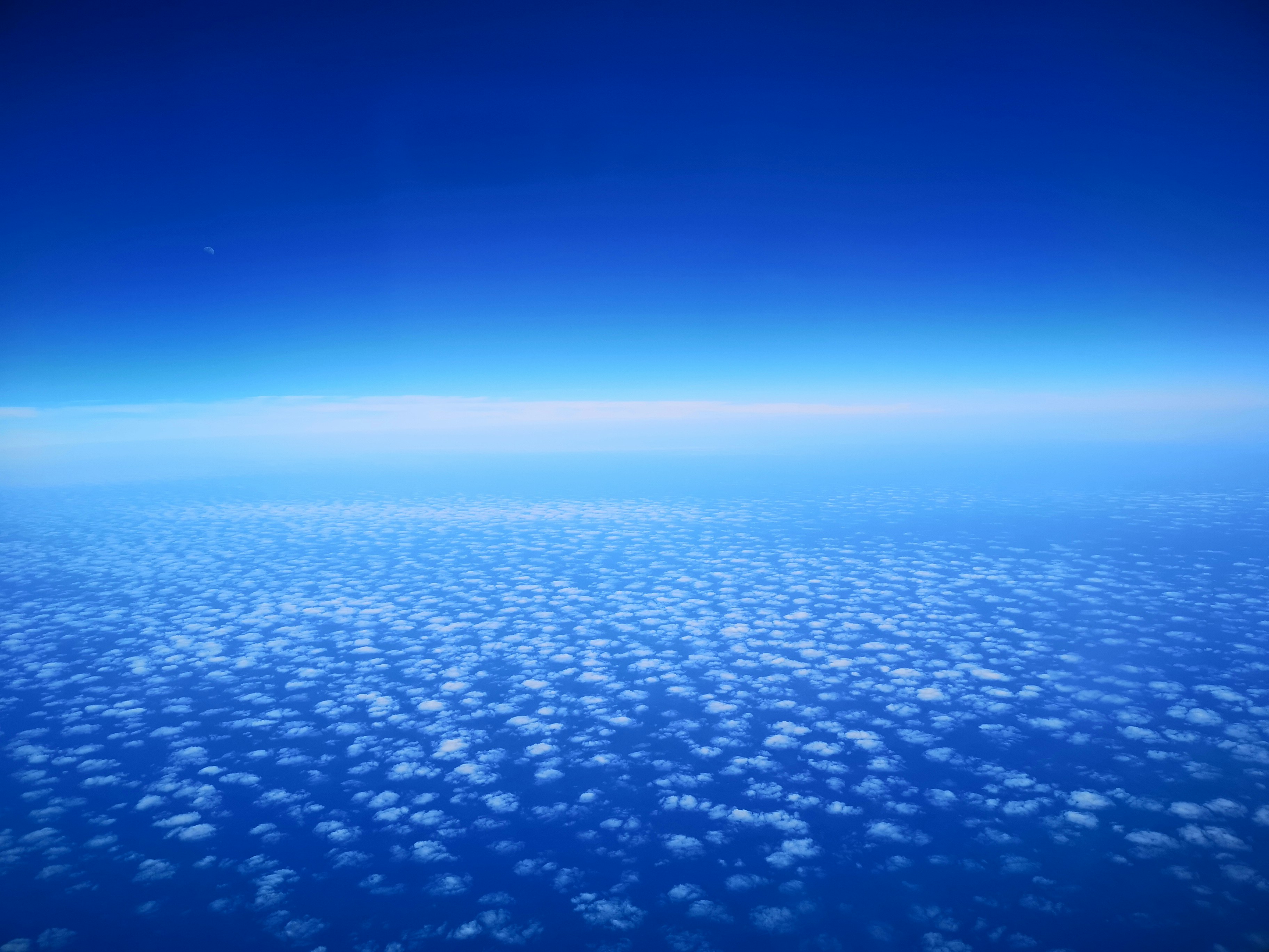 Expansive aerial view of fluffy clouds over a deep blue sea under a vibrant sky.