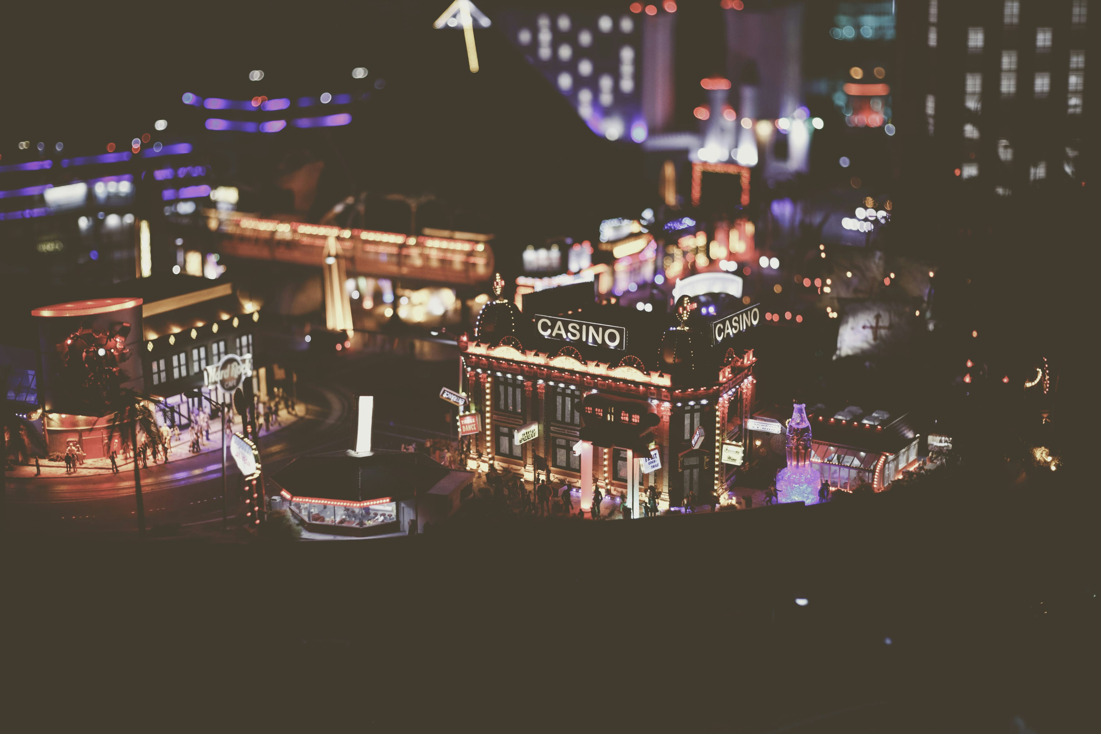 A vibrant miniature casino scene illuminated by colorful lights, showcasing intricate details of the structures and surrounding attractions.