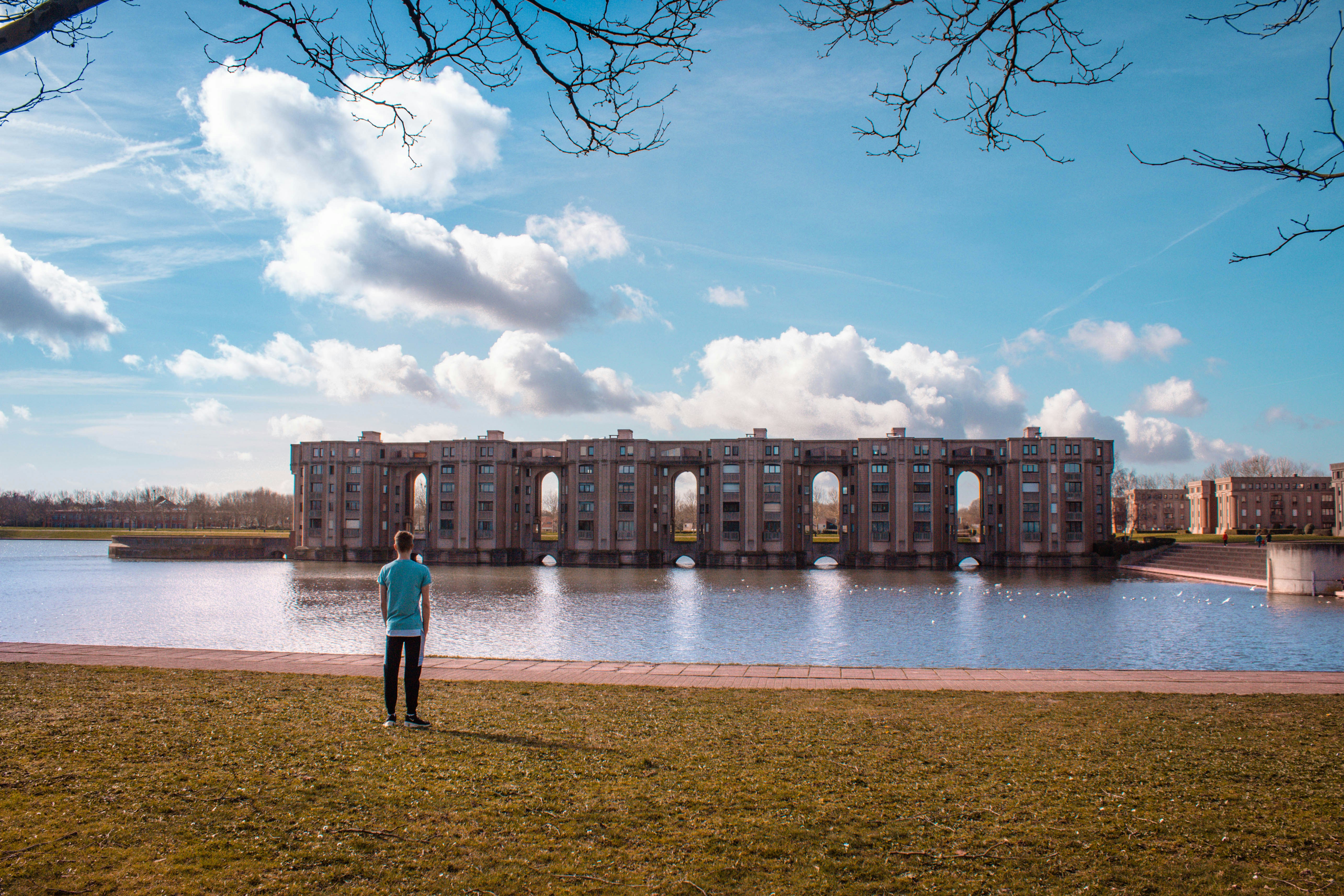 Man standing near body of water with building in between photo – Free ...