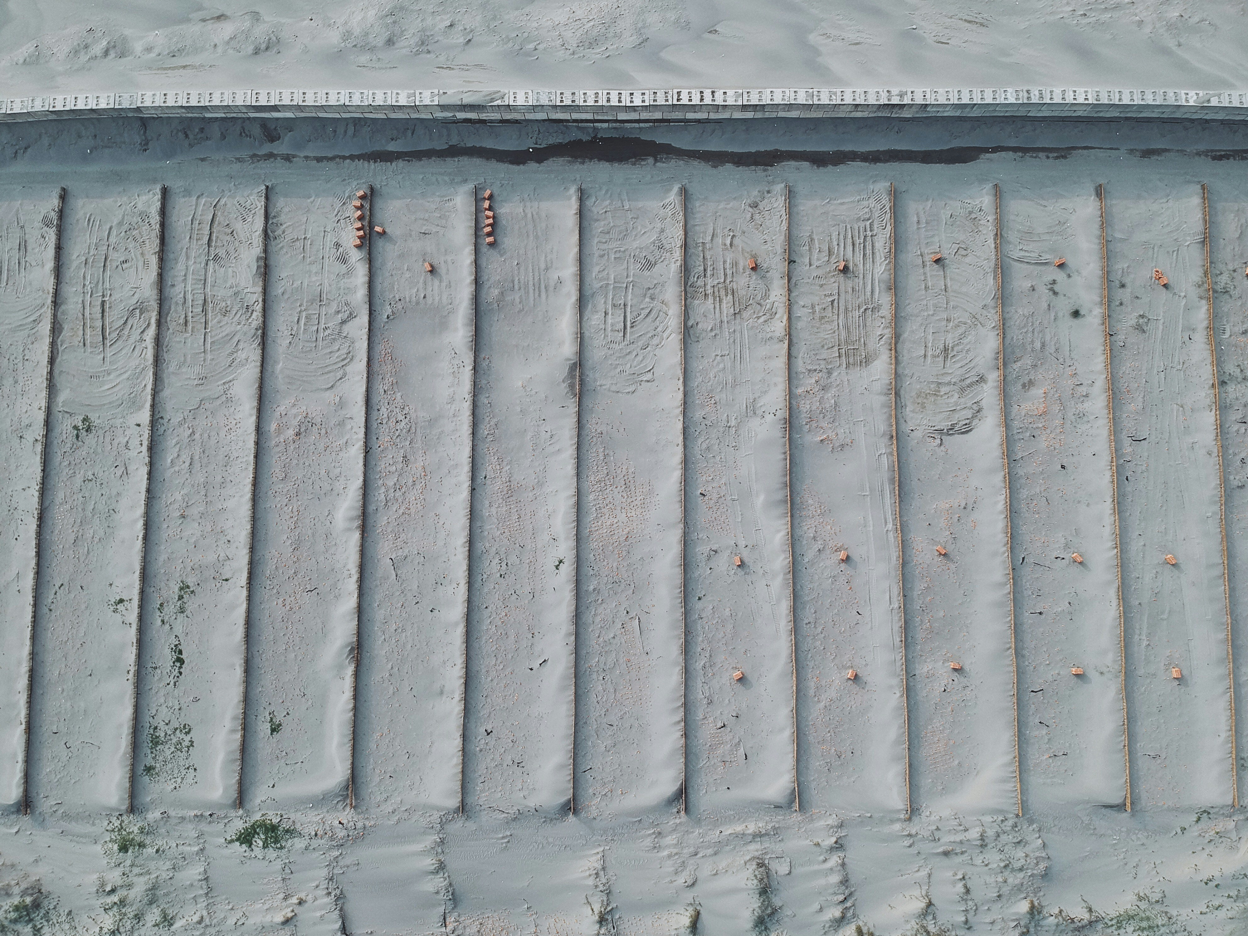 Aerial view of evenly spaced, snow-covered rows creating a pattern in a field.
