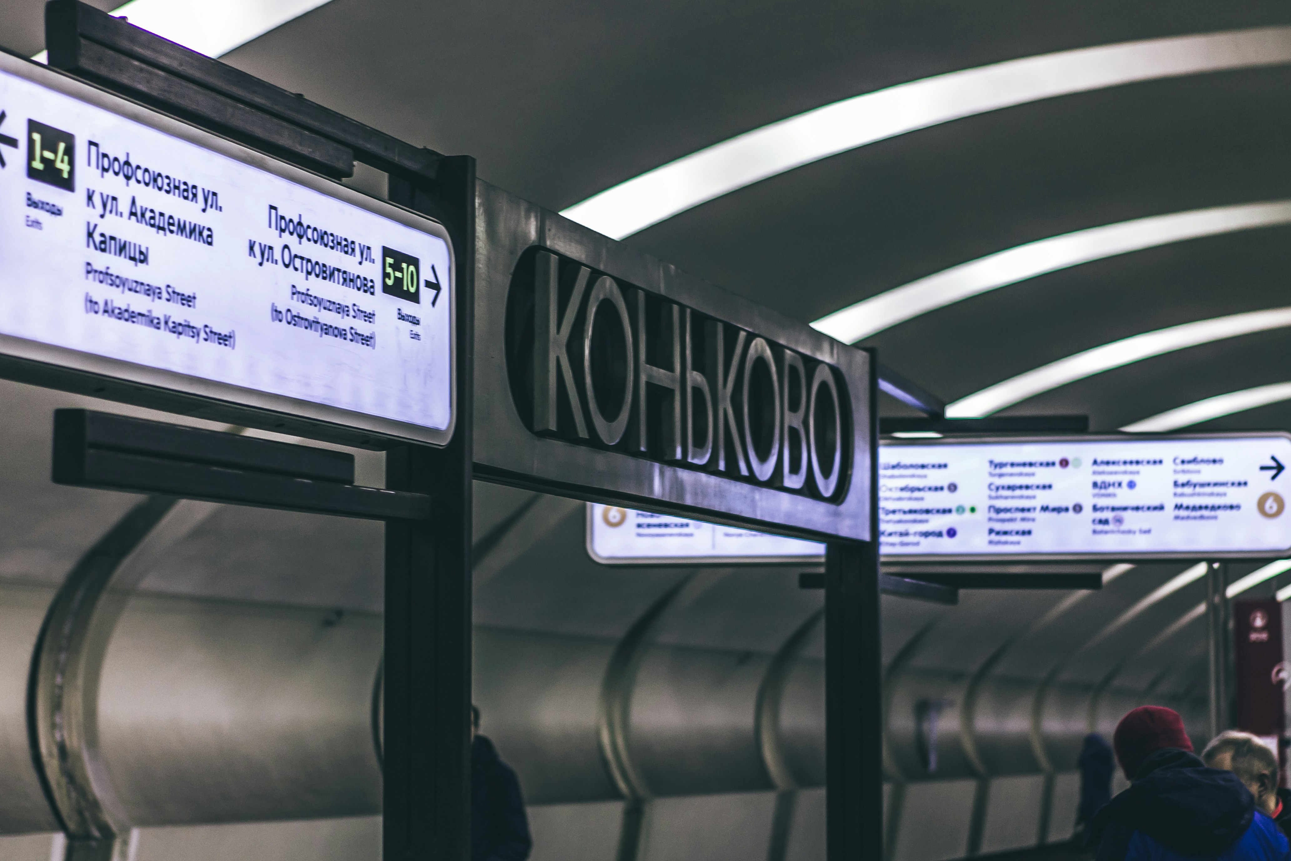 Subway station with illuminated signs and a curved, modern ceiling design.