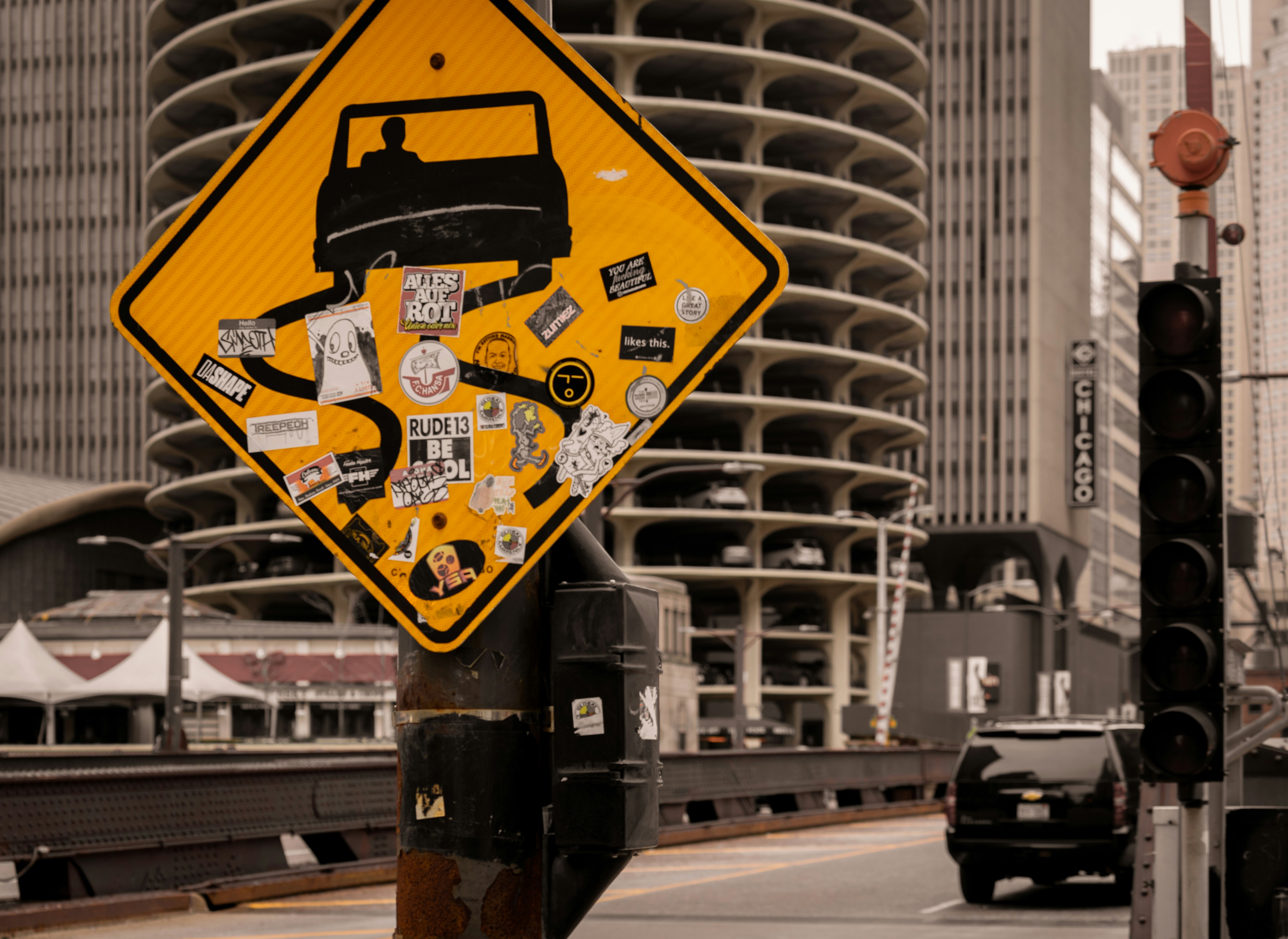 Stickered Warning: A Yellow Crossing Sign Framed by Urban Concrete