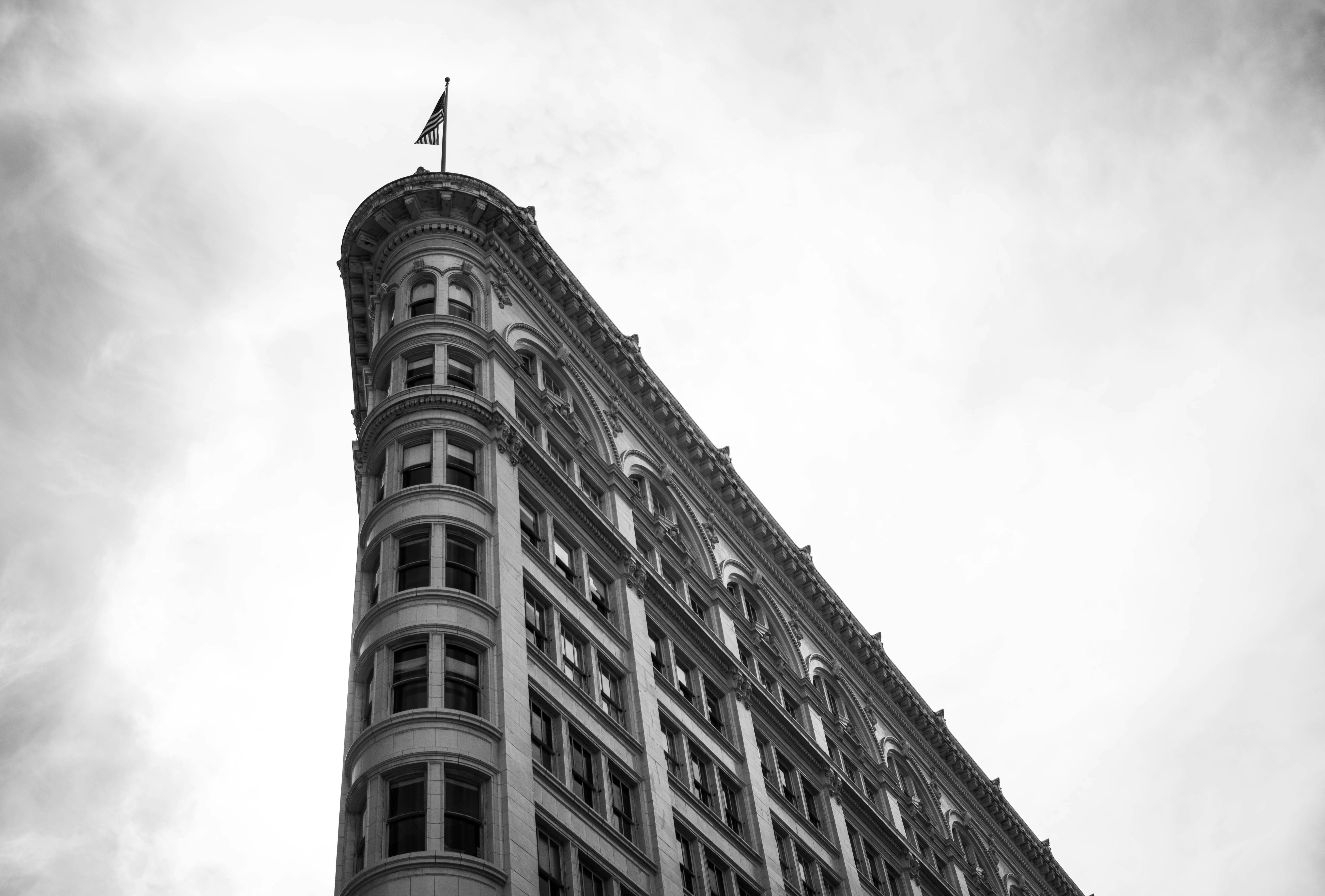 Historic building with a distinctive curved facade, captured in monochrome, showcasing intricate architectural details against a cloudy sky.