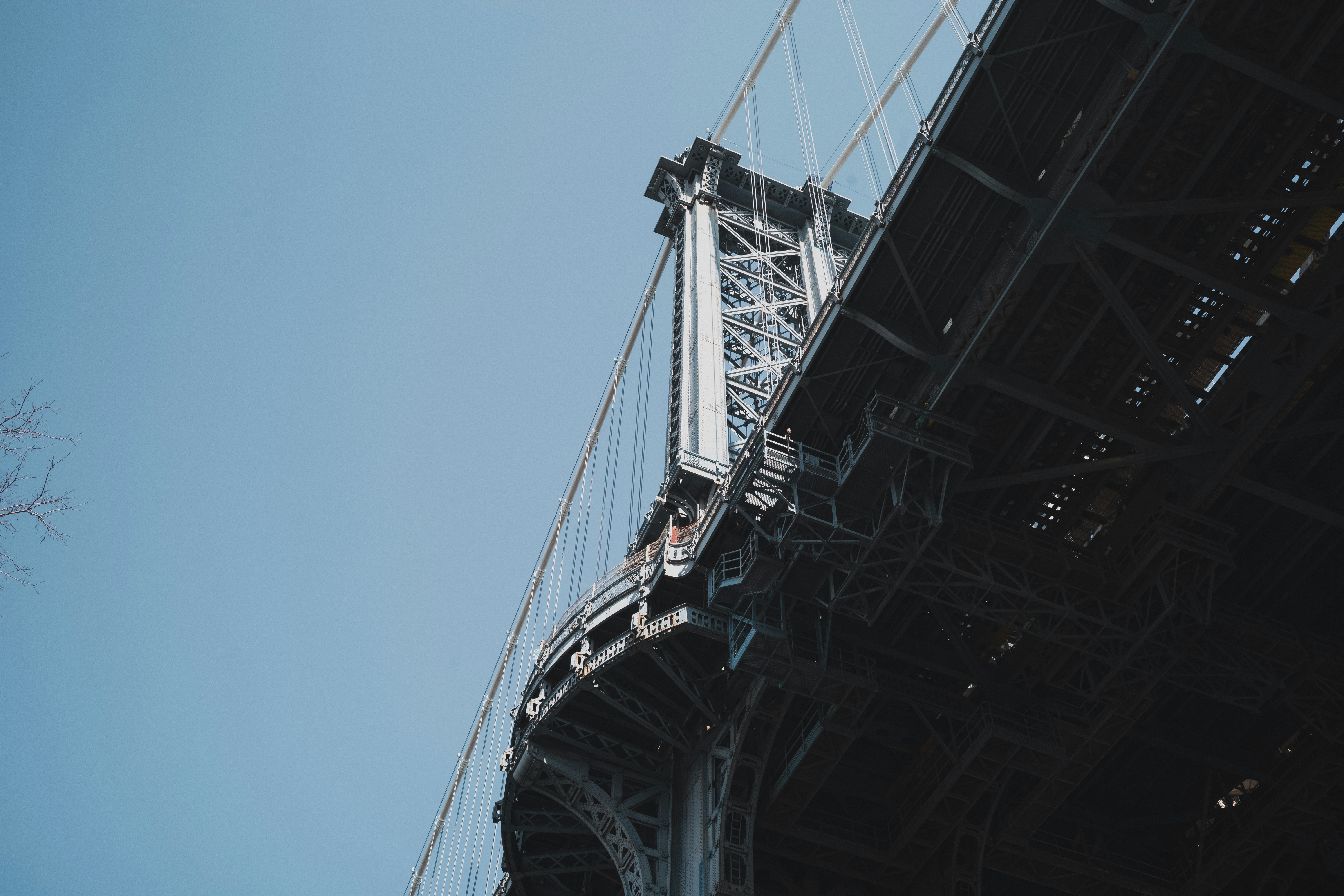Detailed view of the underside of a bridge, showcasing its intricate steel framework against a clear blue sky.