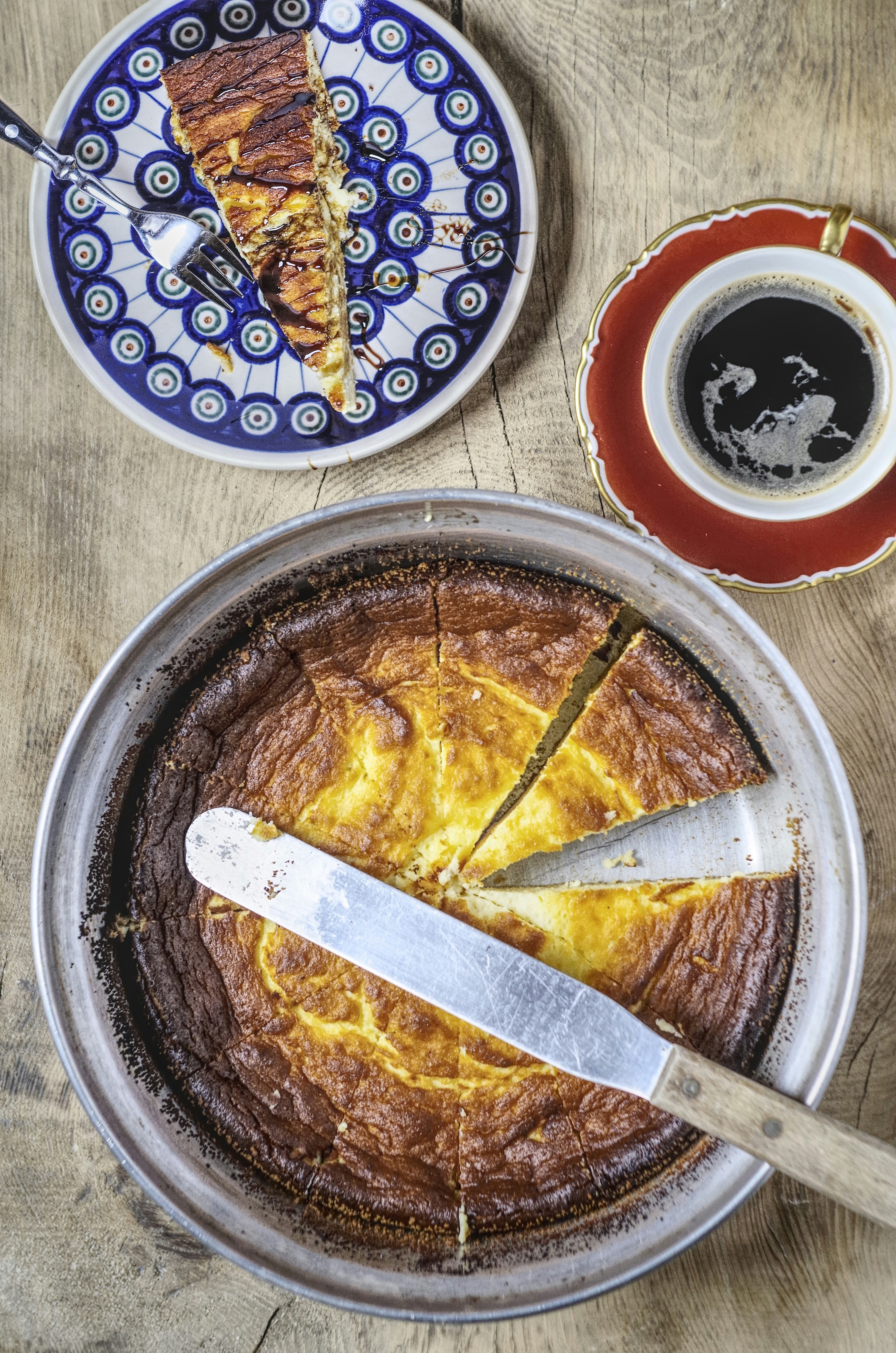 A Sunday photo session of cheesecake on wooden table, served in traditional Polish ceramics.