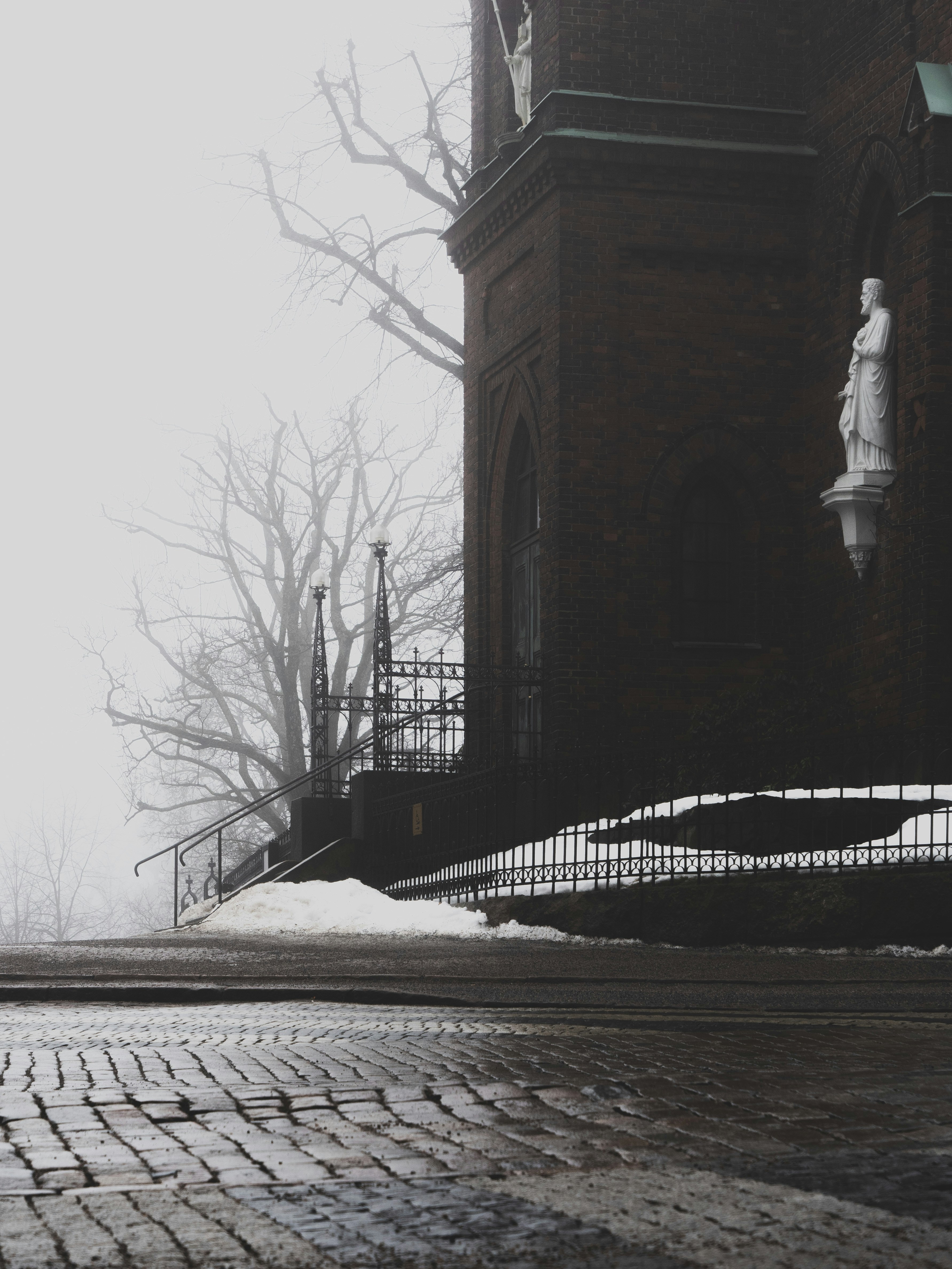 Stone Sentinel in Winter Fog by a Brick Chapel