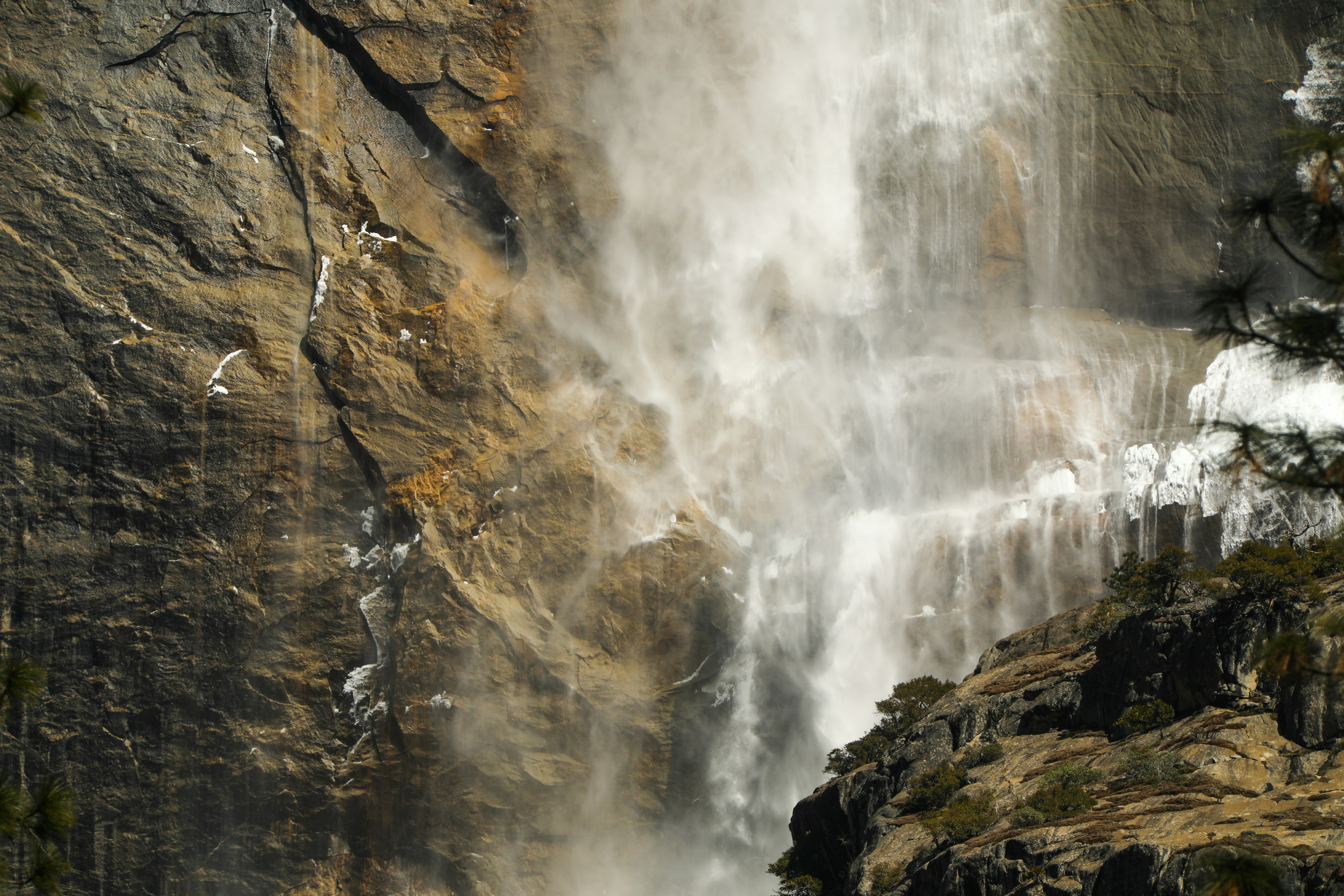 Waterfall cascading down a rocky cliff surrounded by mist and lush vegetation.
