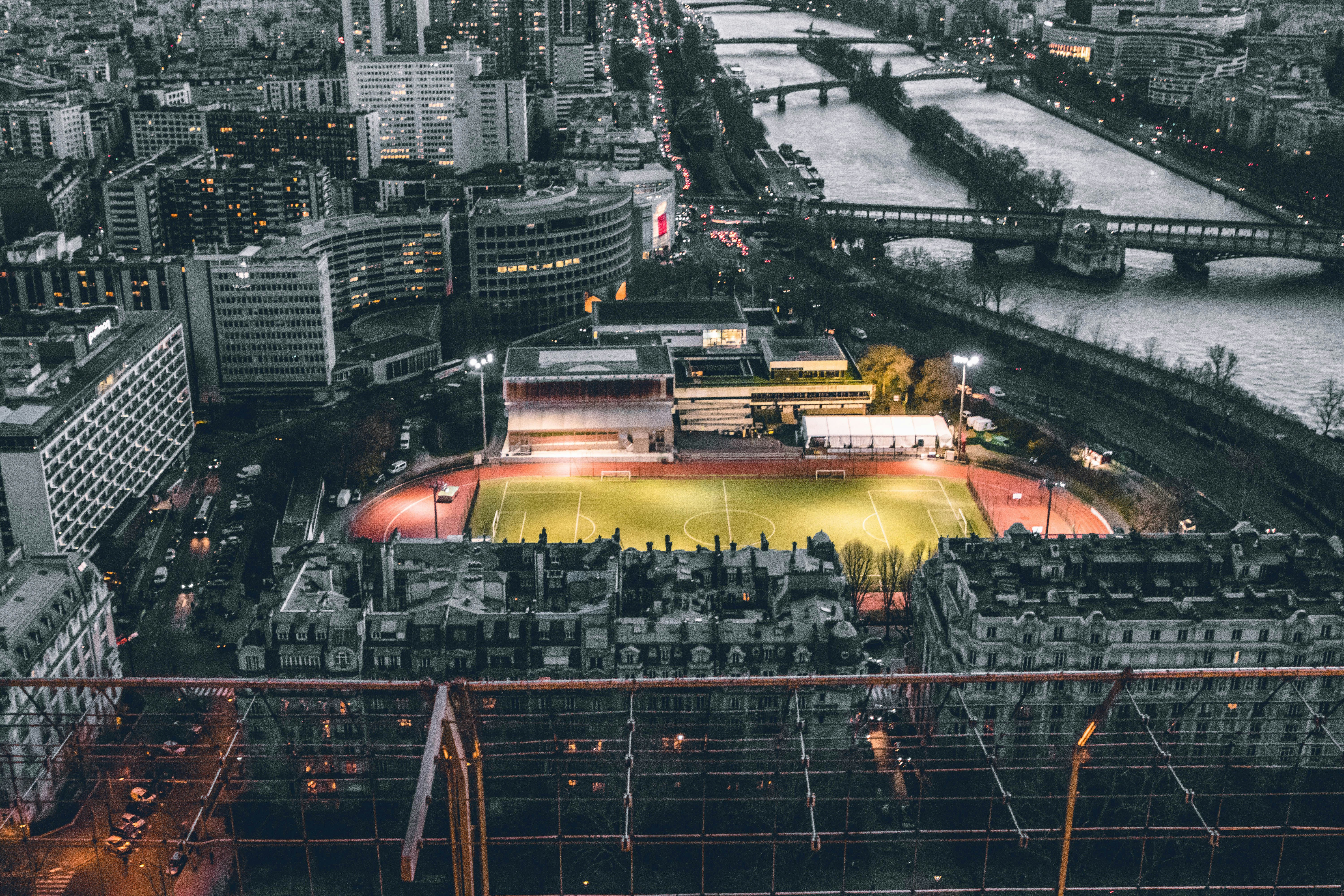 Emerald Field in a Grayscale Cityscape: A Stadium's Colorful Heart Amid the Quiet Metropolis