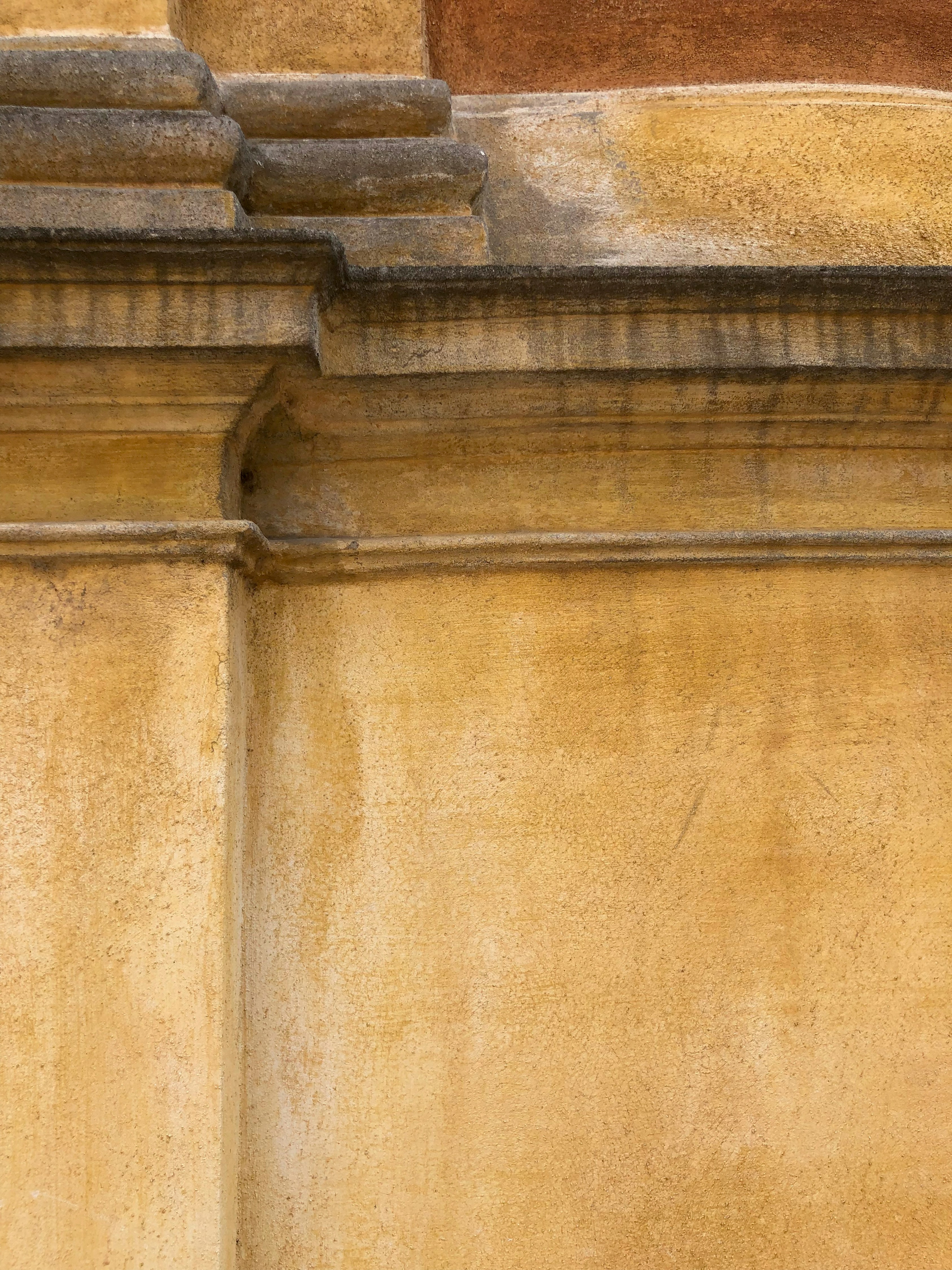 Close-up of a weathered wall showcasing a blend of yellow and brown hues with intricate textures and lines.