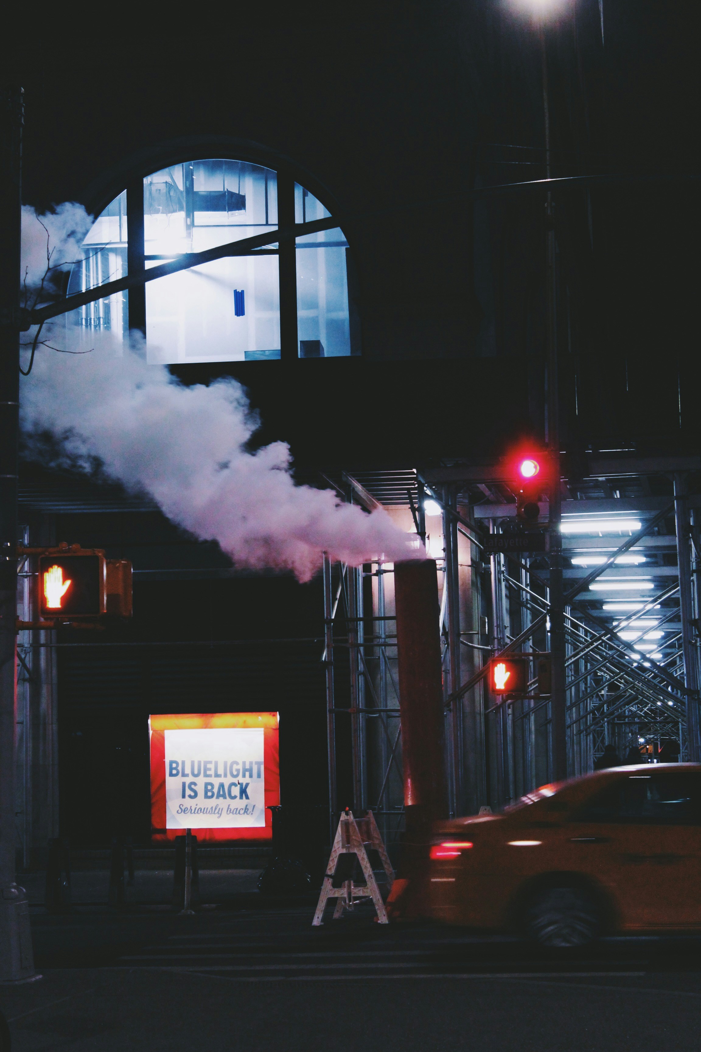 Red Signal in a Scaffolded Night: Steam, Neon, and a Moving Taxi
