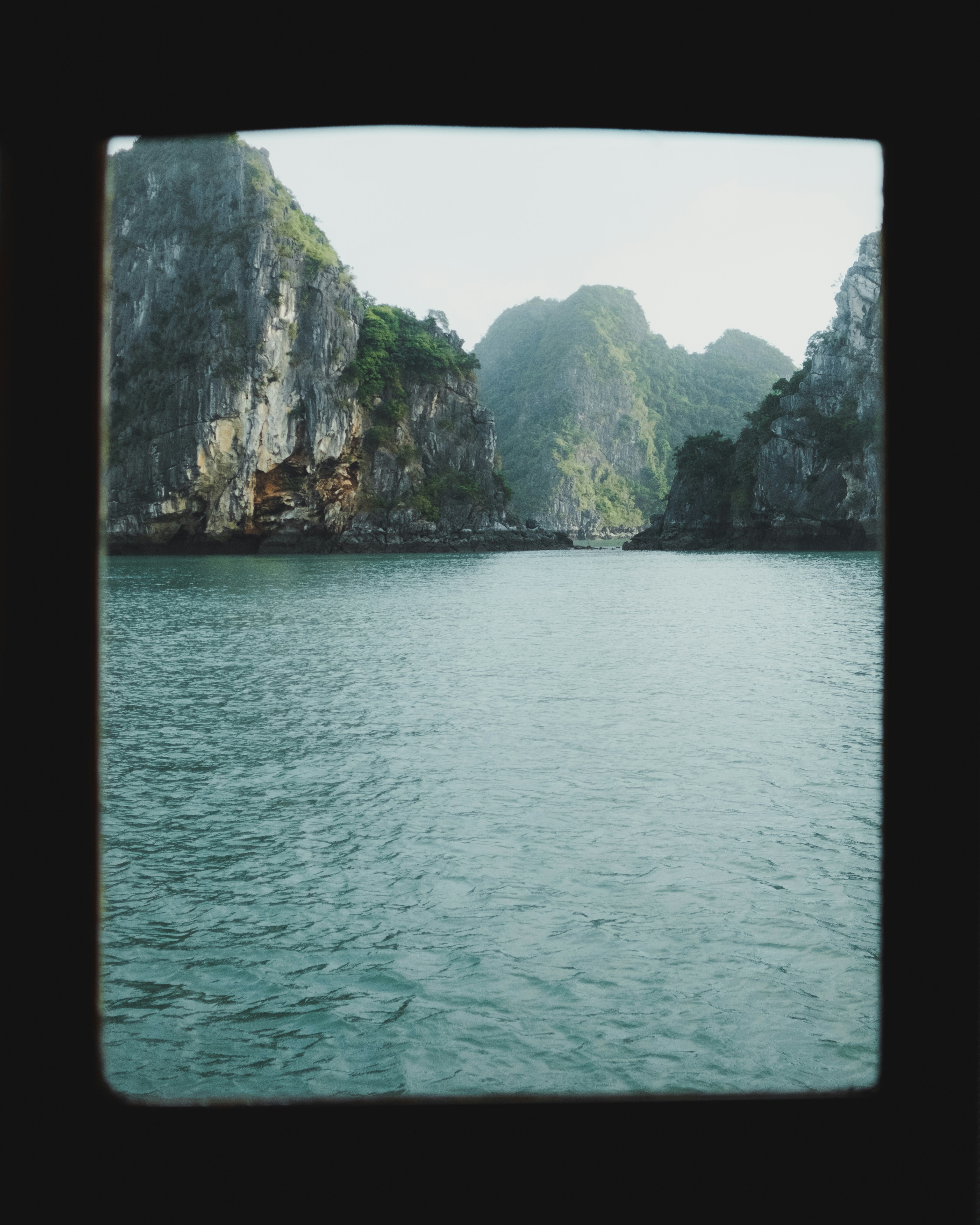 Lush green cliffs frame a calm bay, inviting exploration and serenity. The clear waters reflect the surrounding landscape.