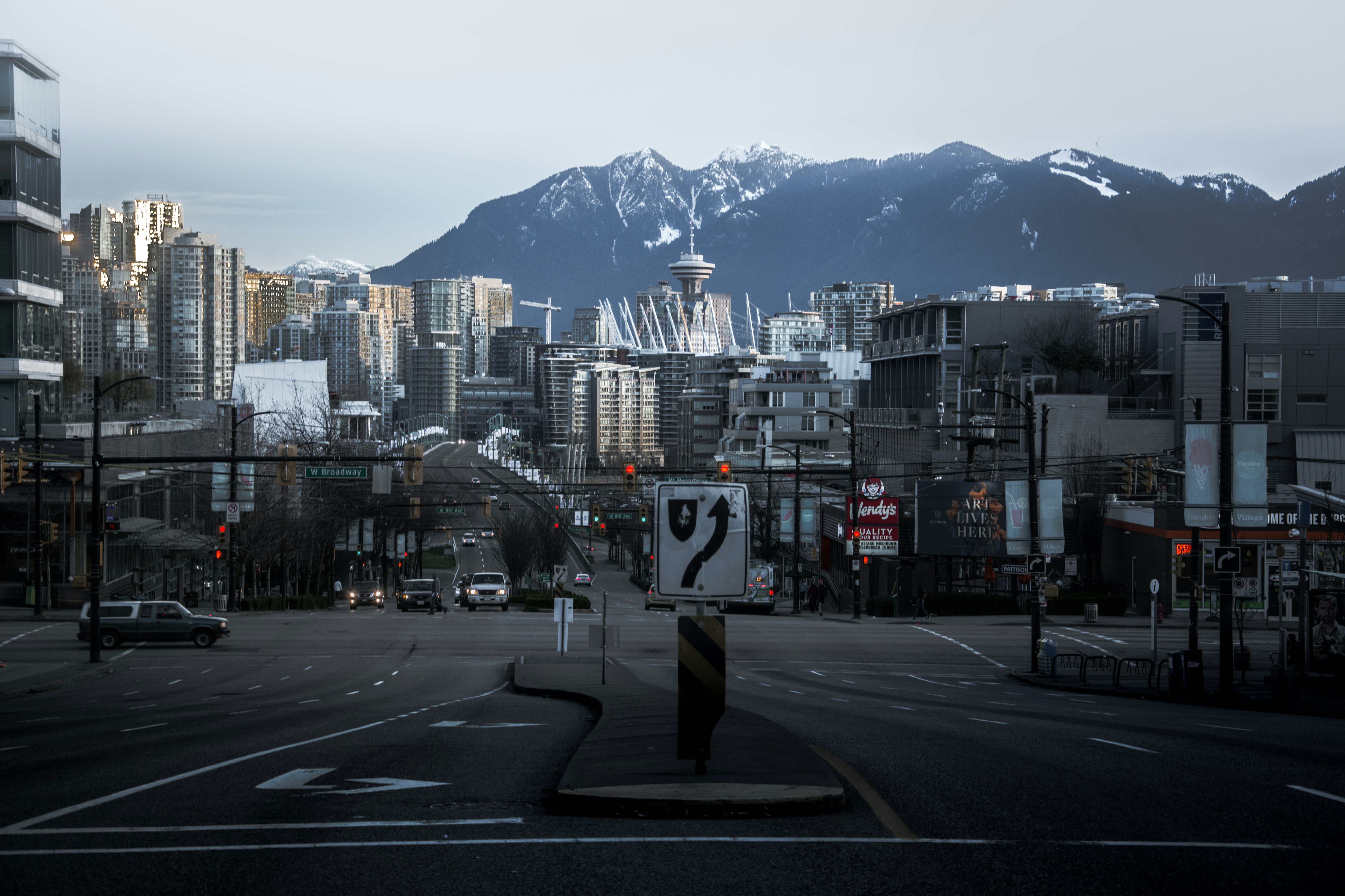 City skyline with towering mountains in the background under a soft, overcast sky.
